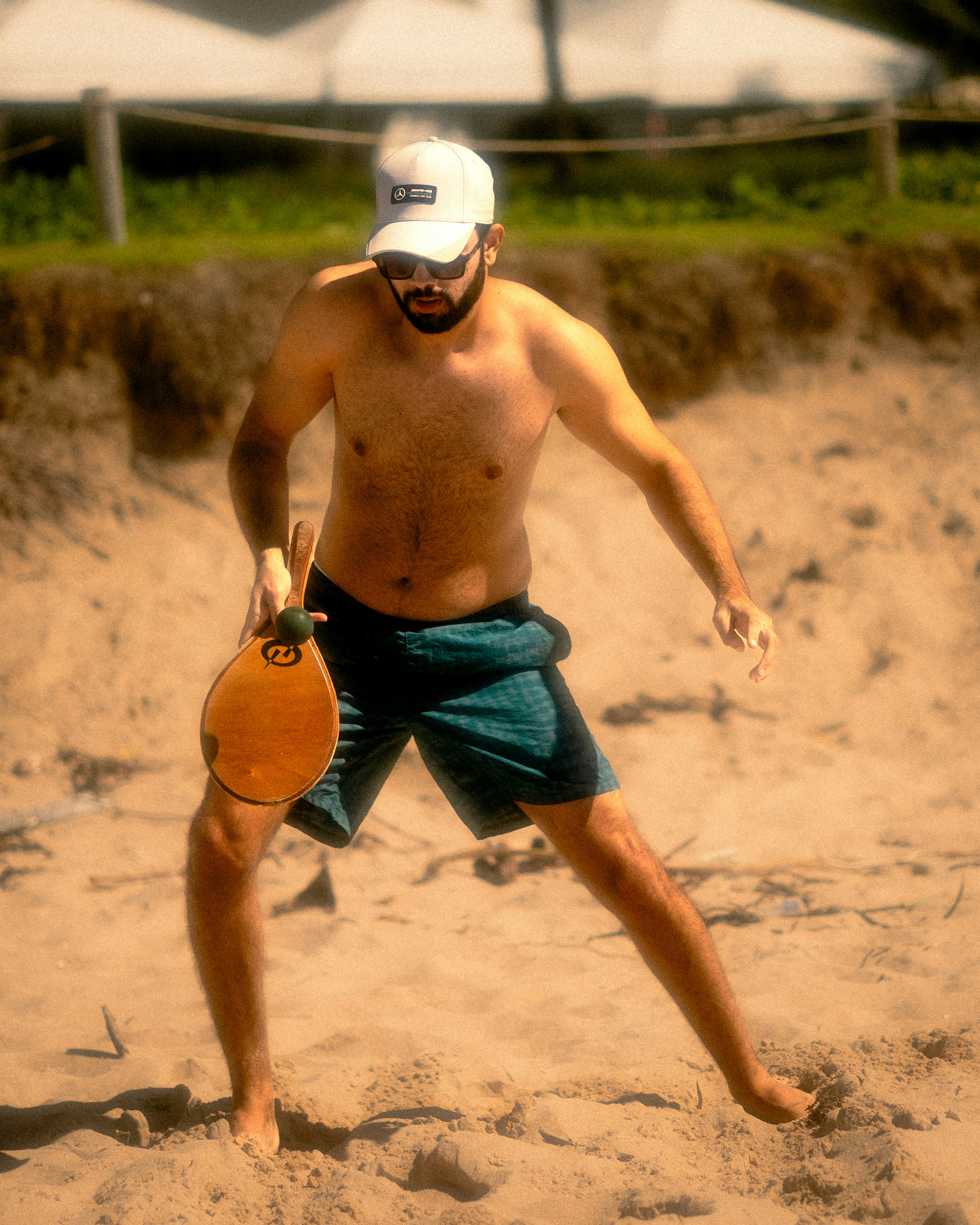 Man playing paddleball on a sandy beach.