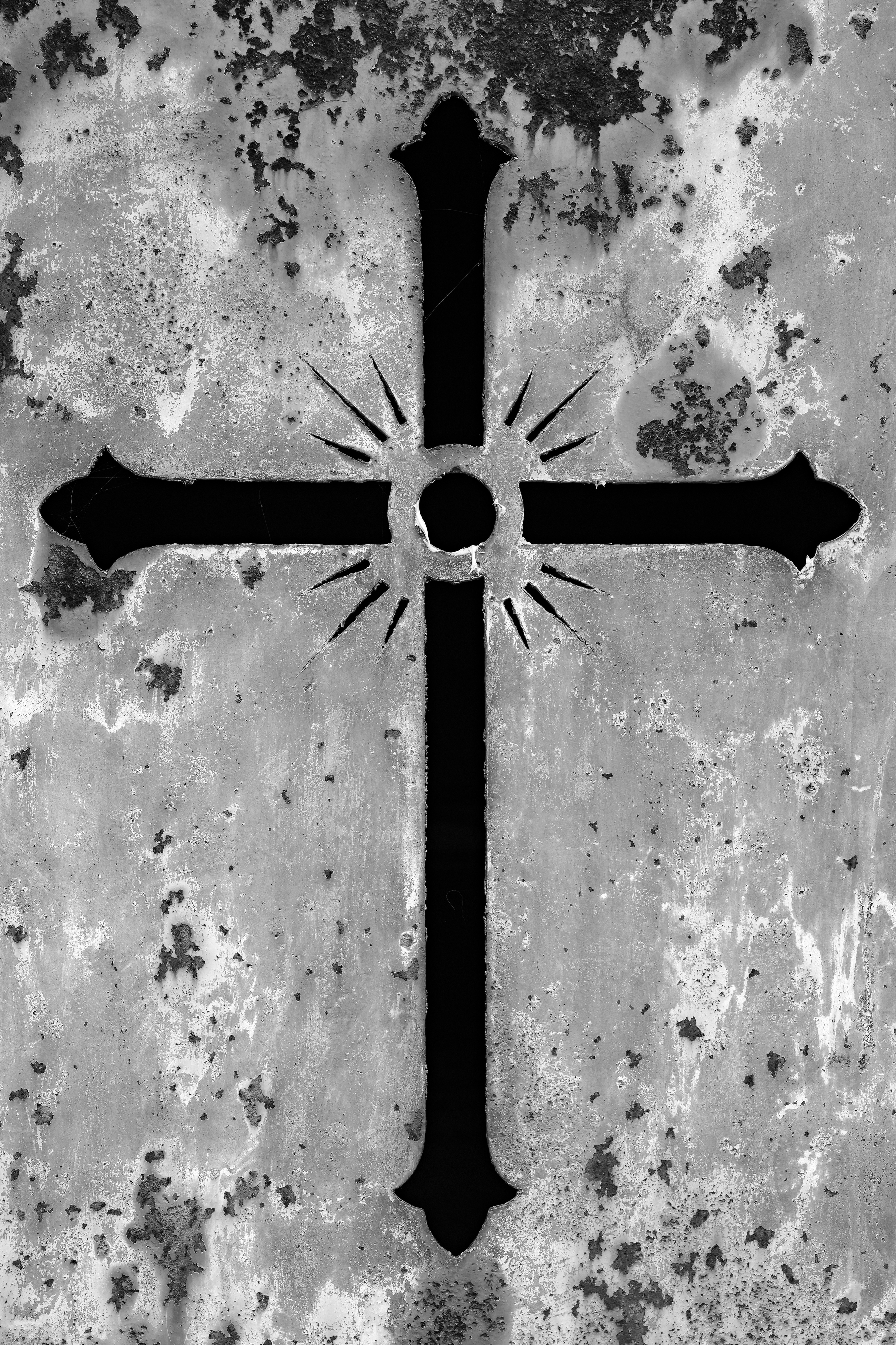 Intricate black cross design etched into a weathered metal surface, highlighting the contrast between spirituality and decay.