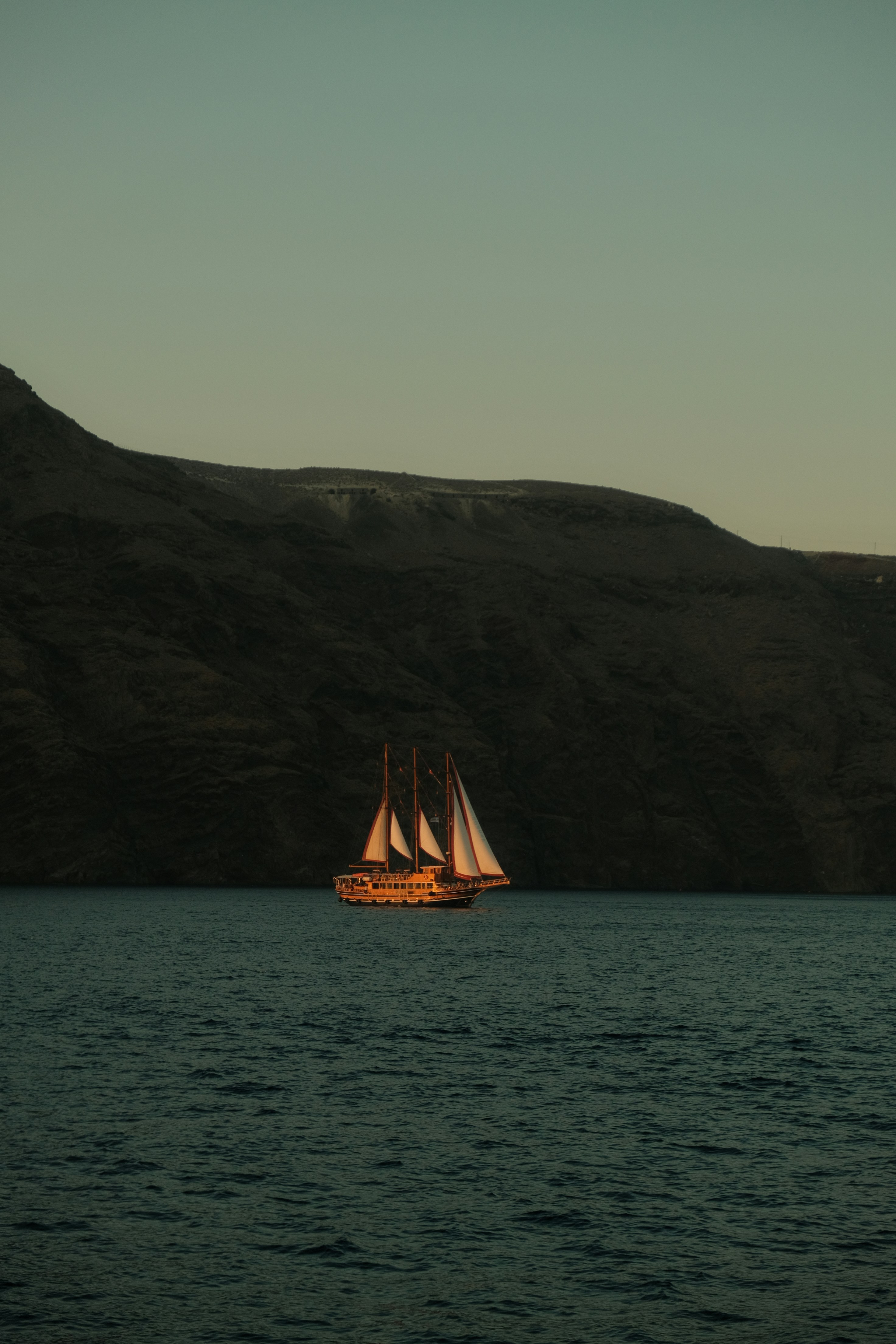 Sunset on a boat | Sailboat on the water with mountains behind