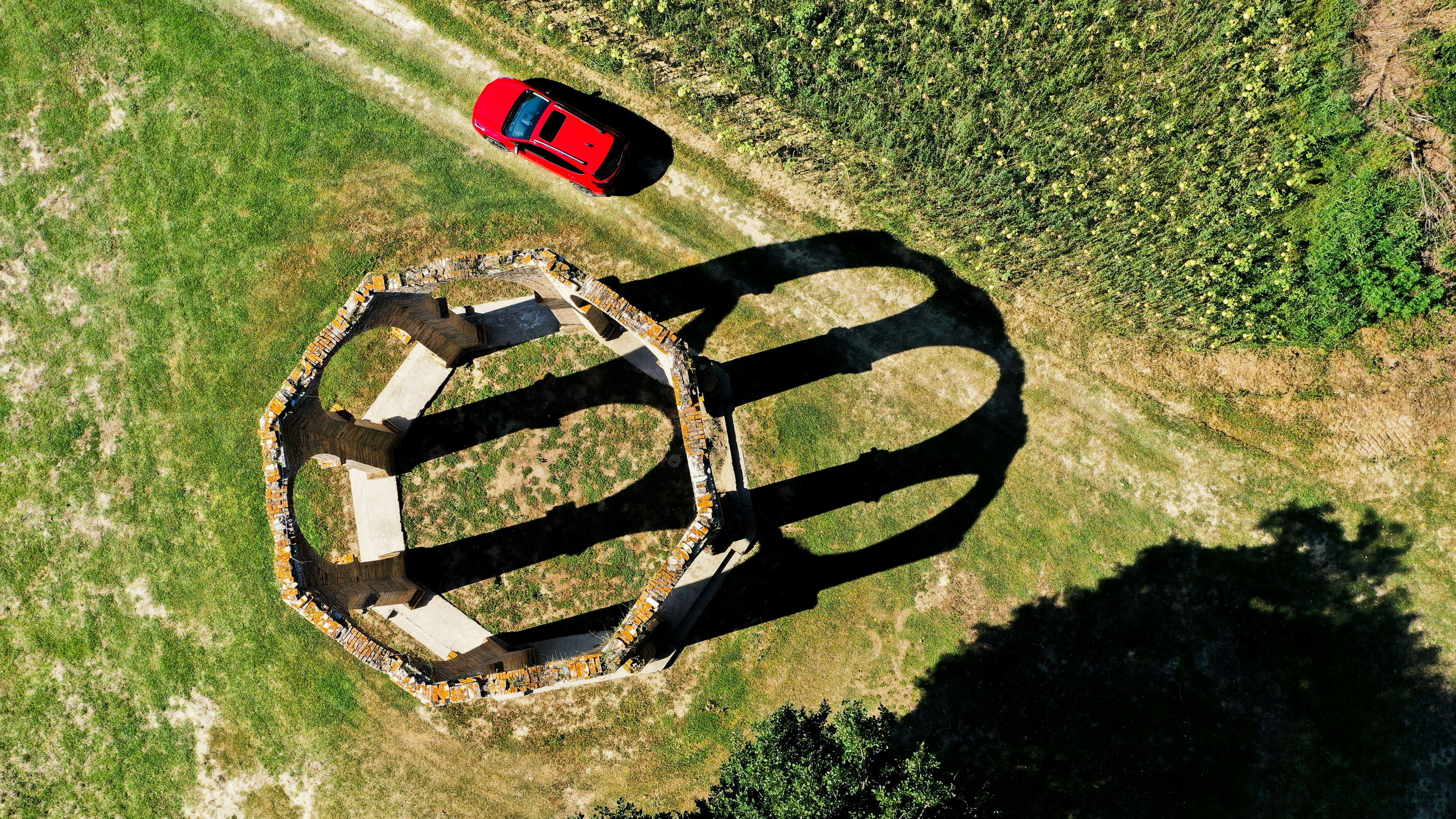 ASMAINTITLE | Aerial view of red car near ancient ruins