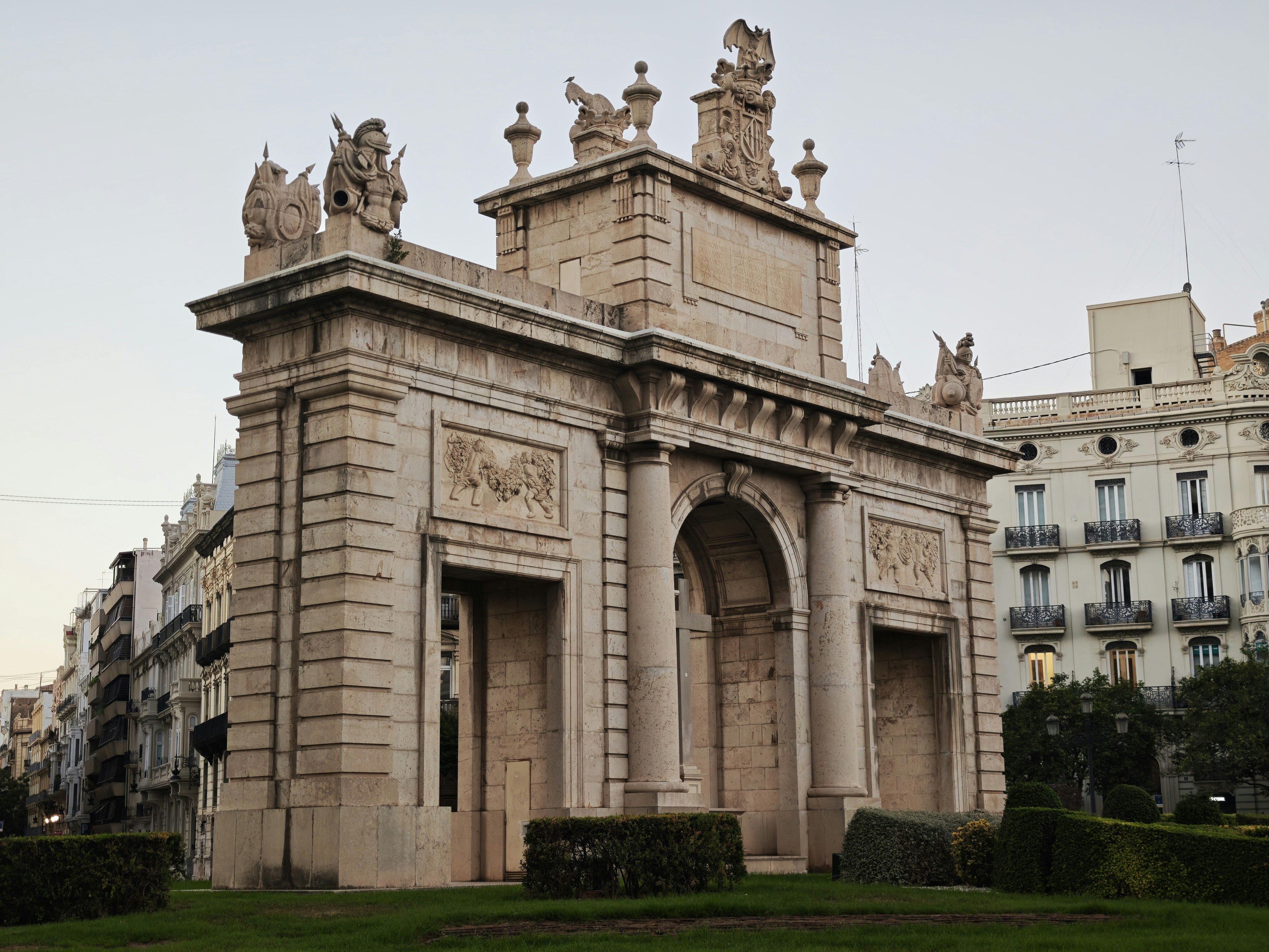 Ornate stone archway with sculptures and buildings behind.