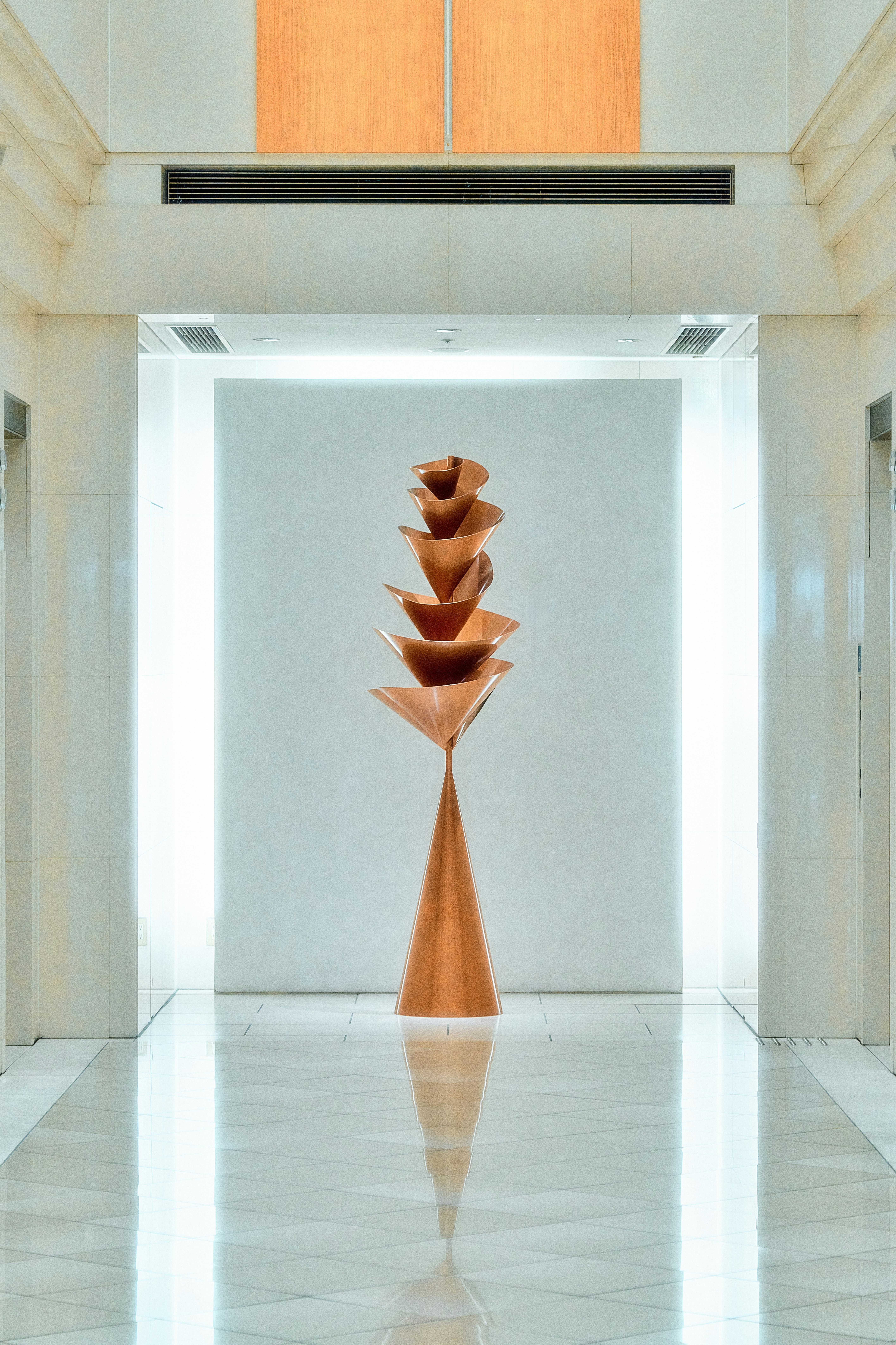 Modern copper sculpture in a well-lit hallway.