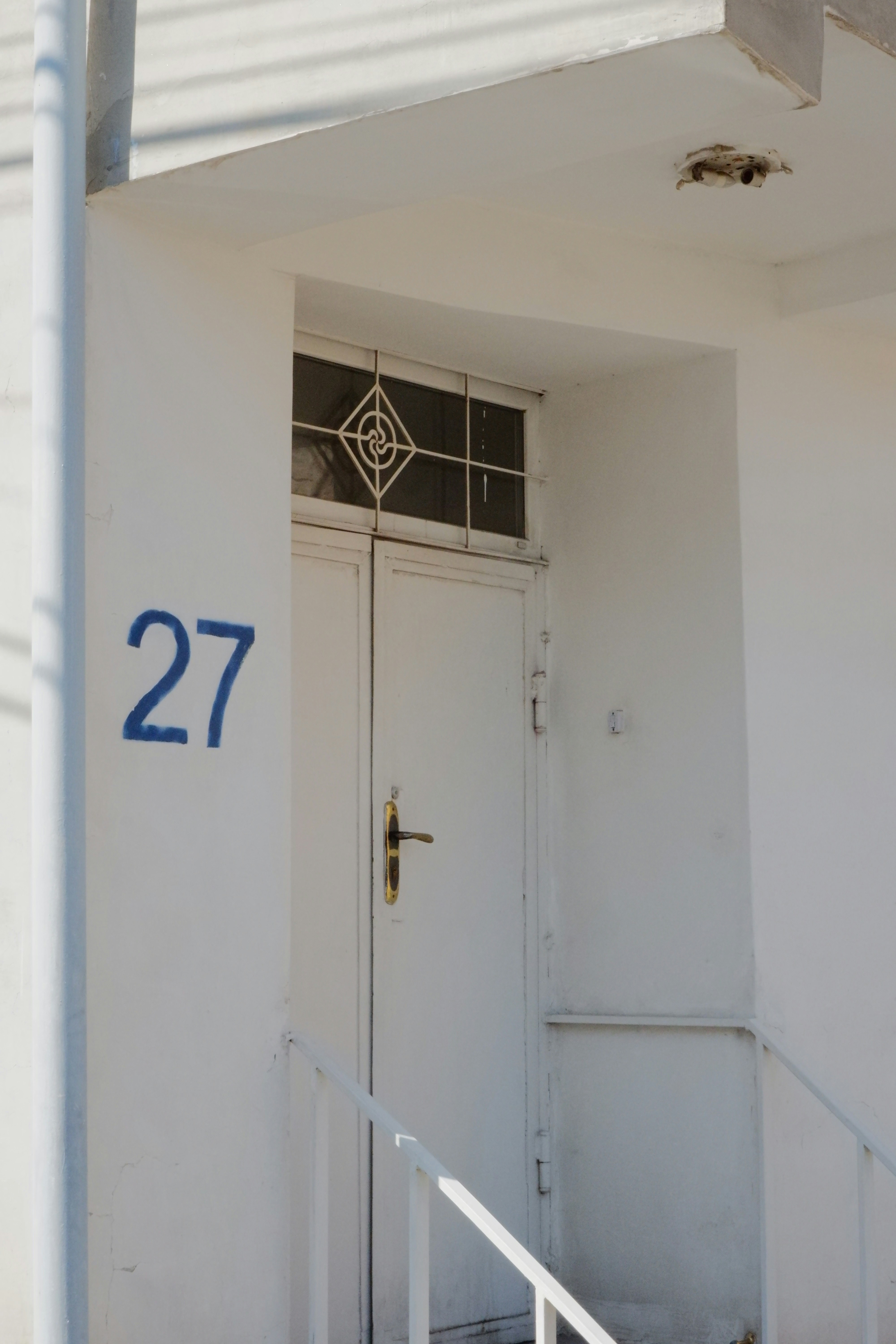 27 in White: A Quiet Doorway Framed by a Diamond Transom