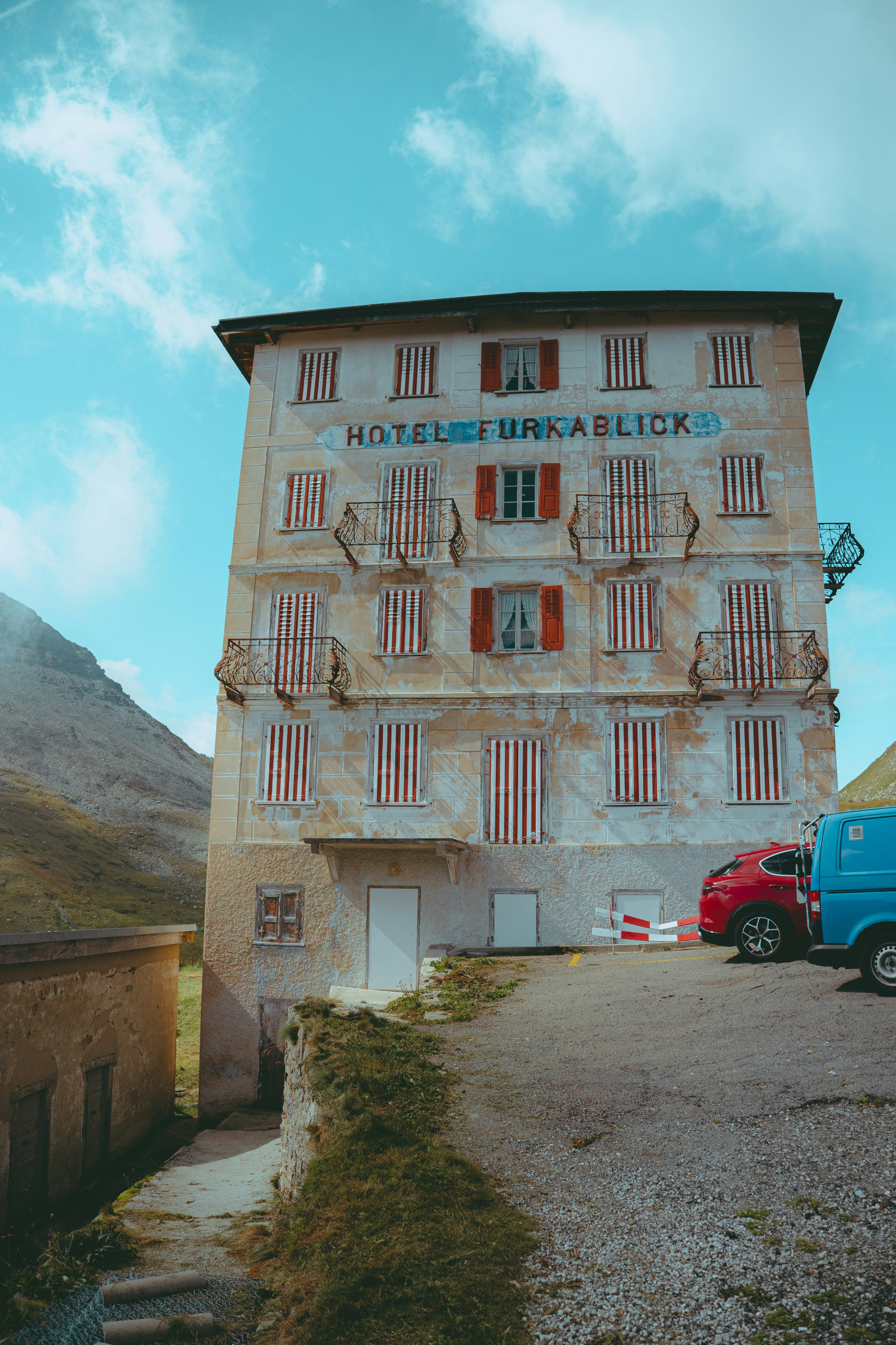 Sunlit Alpine Hotel Facade with Striped Windows and Mountain Road