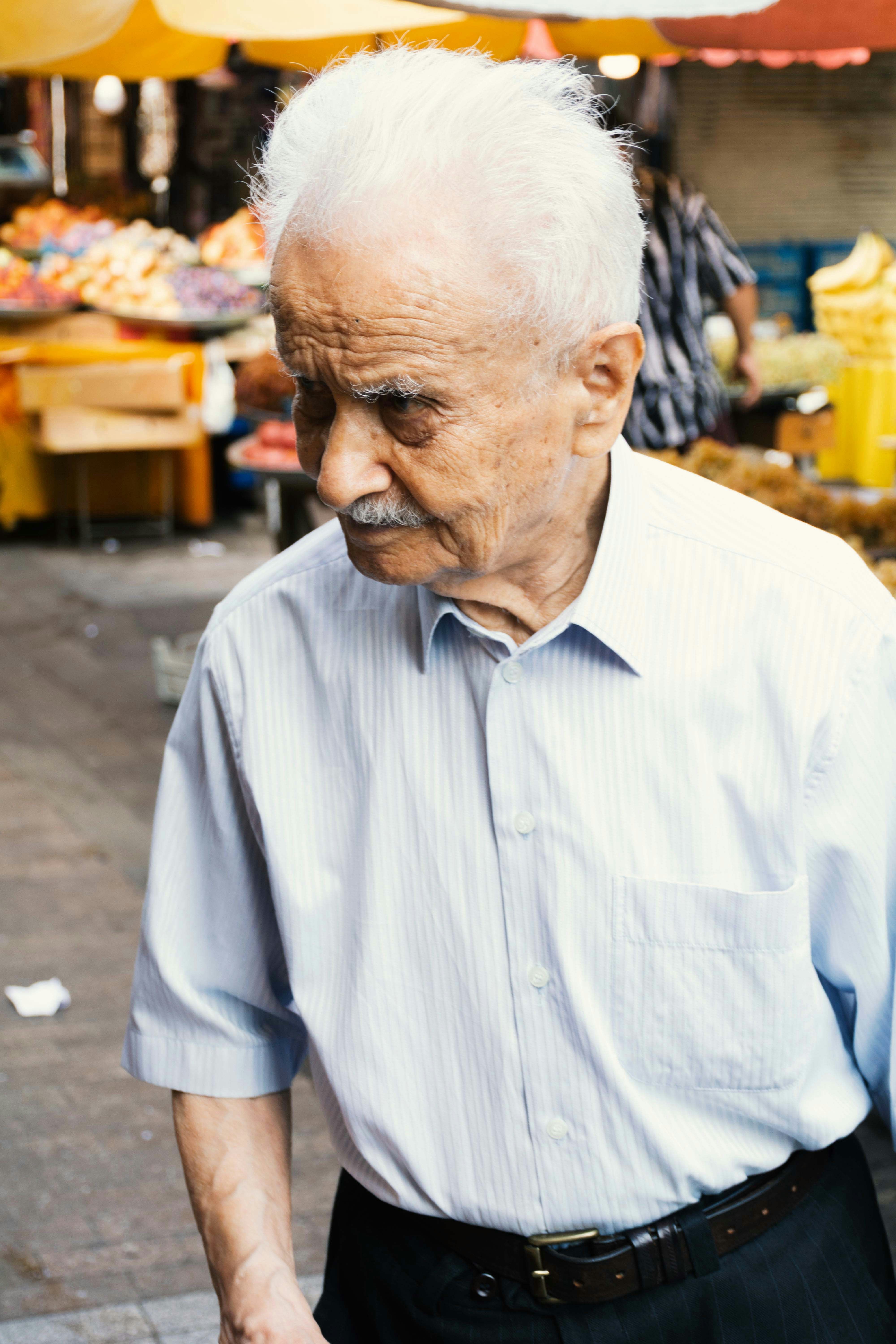 Elderly man in a striped shirt at a market.