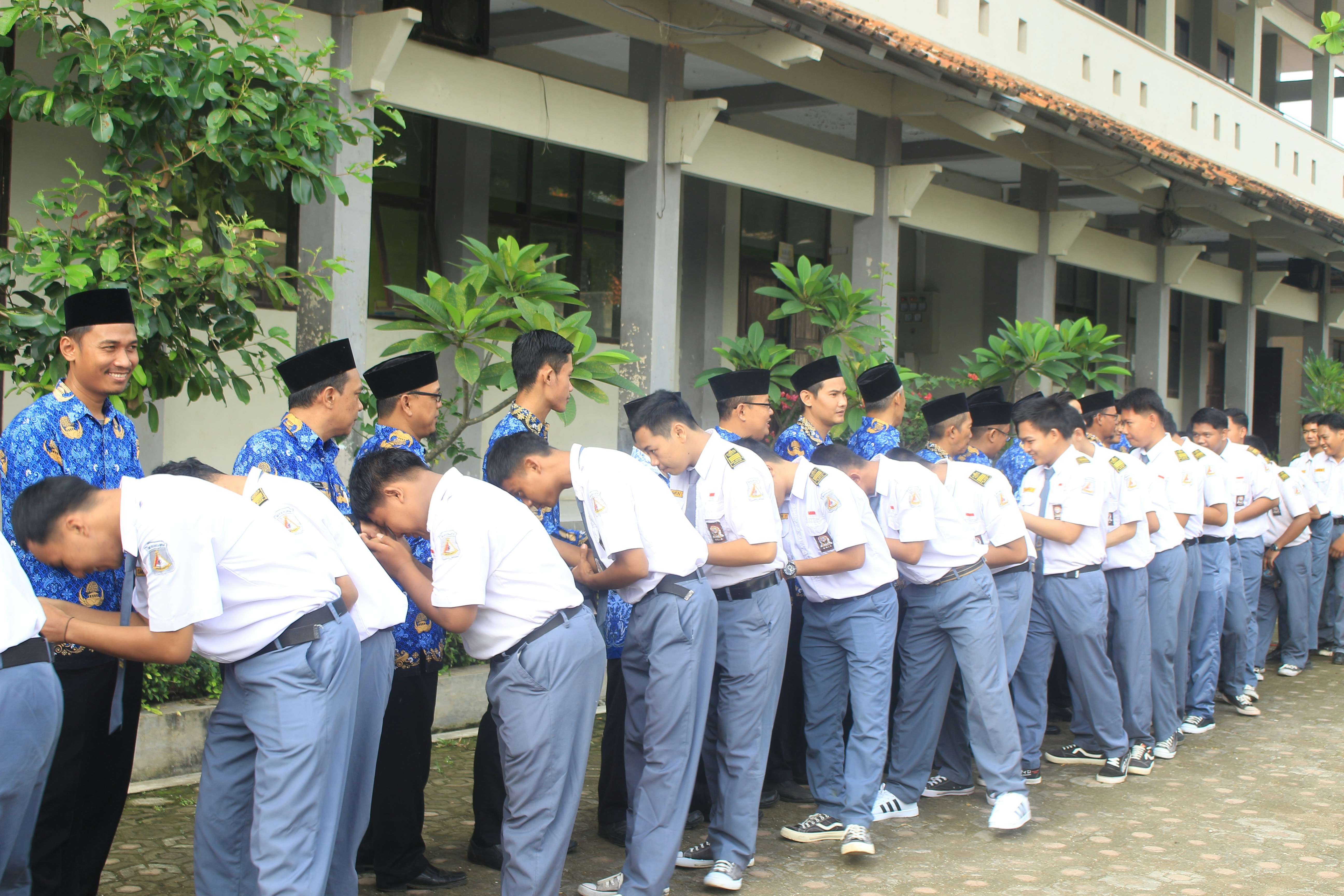 Students in uniform line up and bow respectfully.
