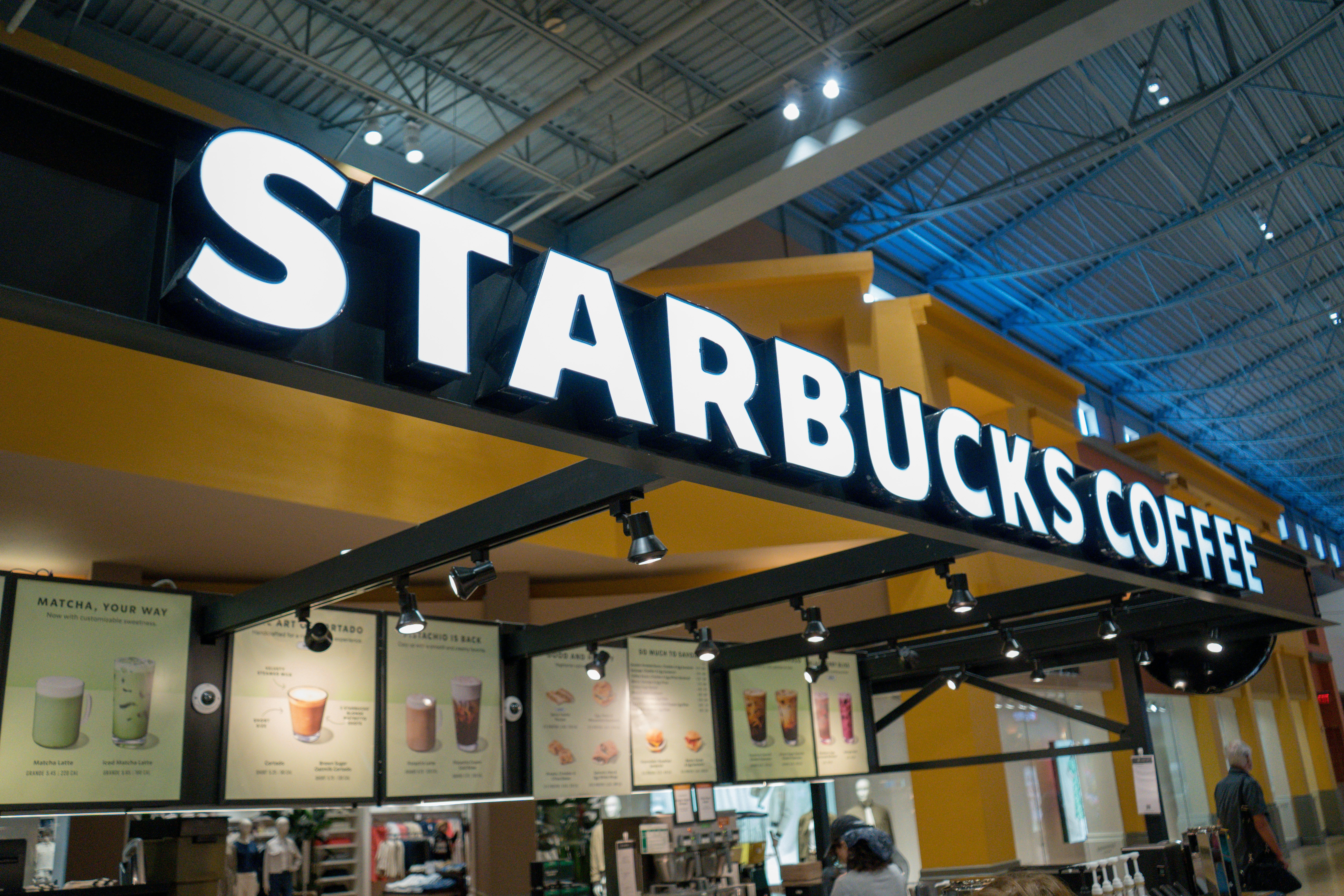 Illuminated Starbucks Coffee sign above a menu display showcasing various beverage options in a vibrant café setting.