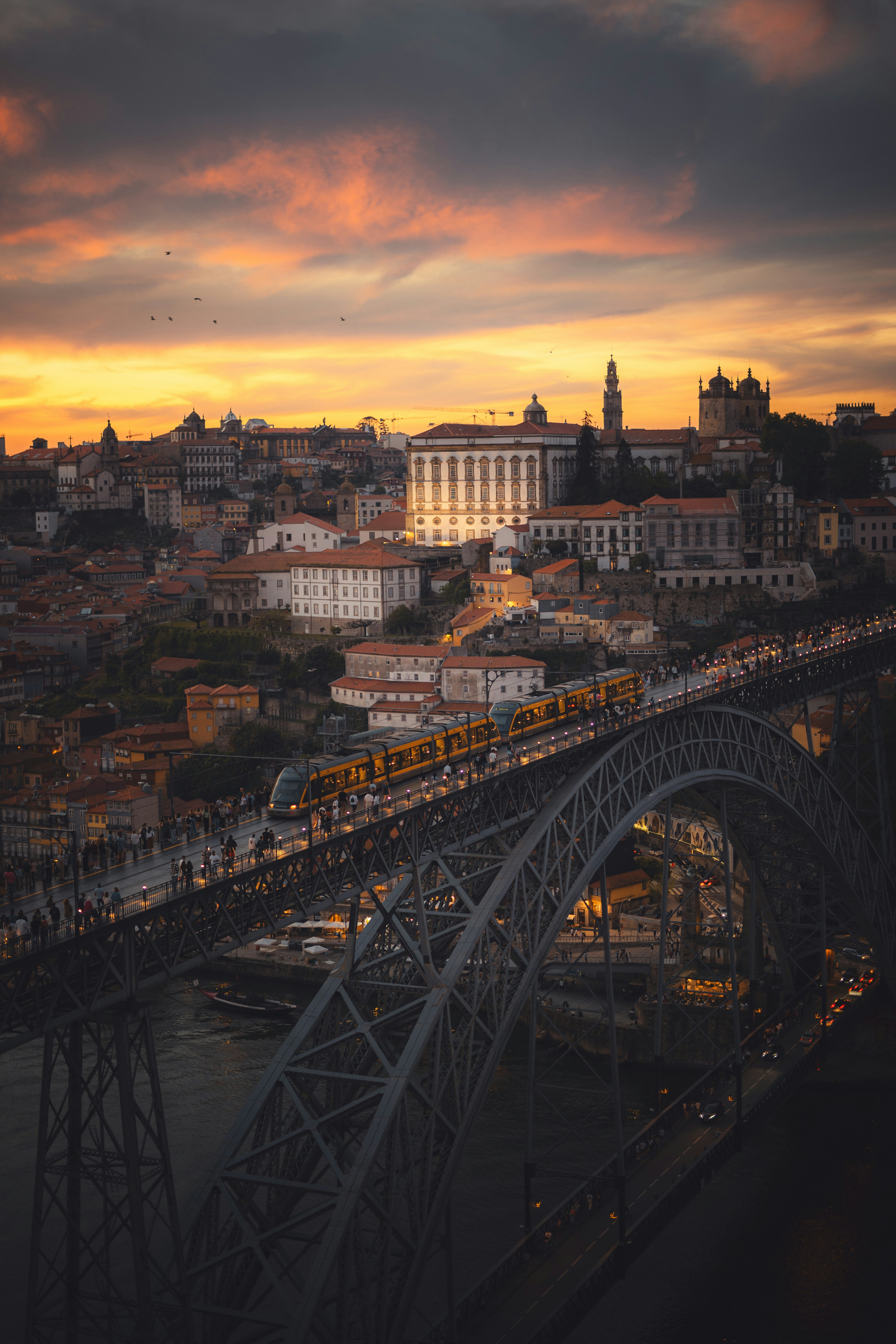 Train crossing a bridge over a river at sunset.