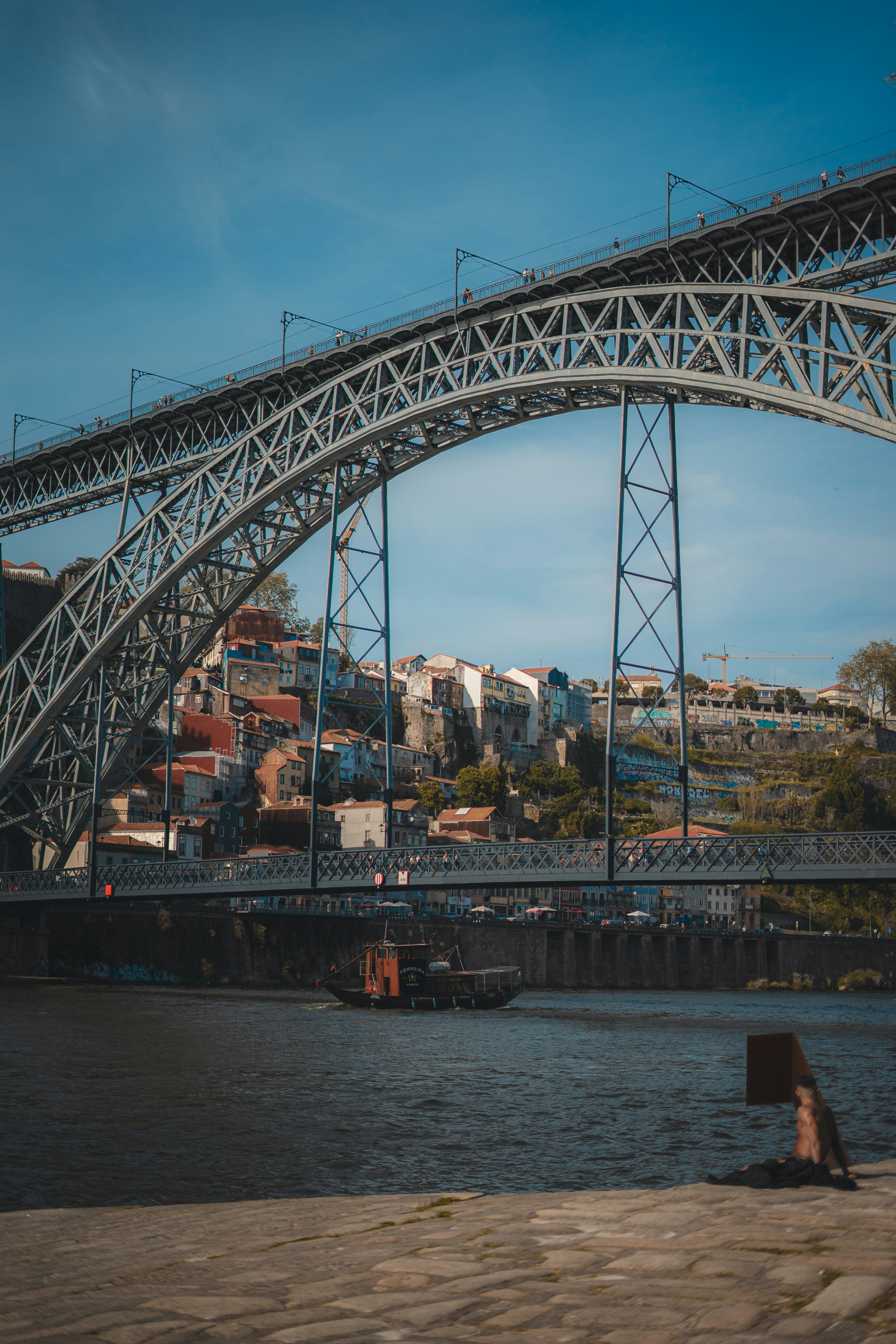 Large metal bridge over a river with city buildings. photo – Free City ...