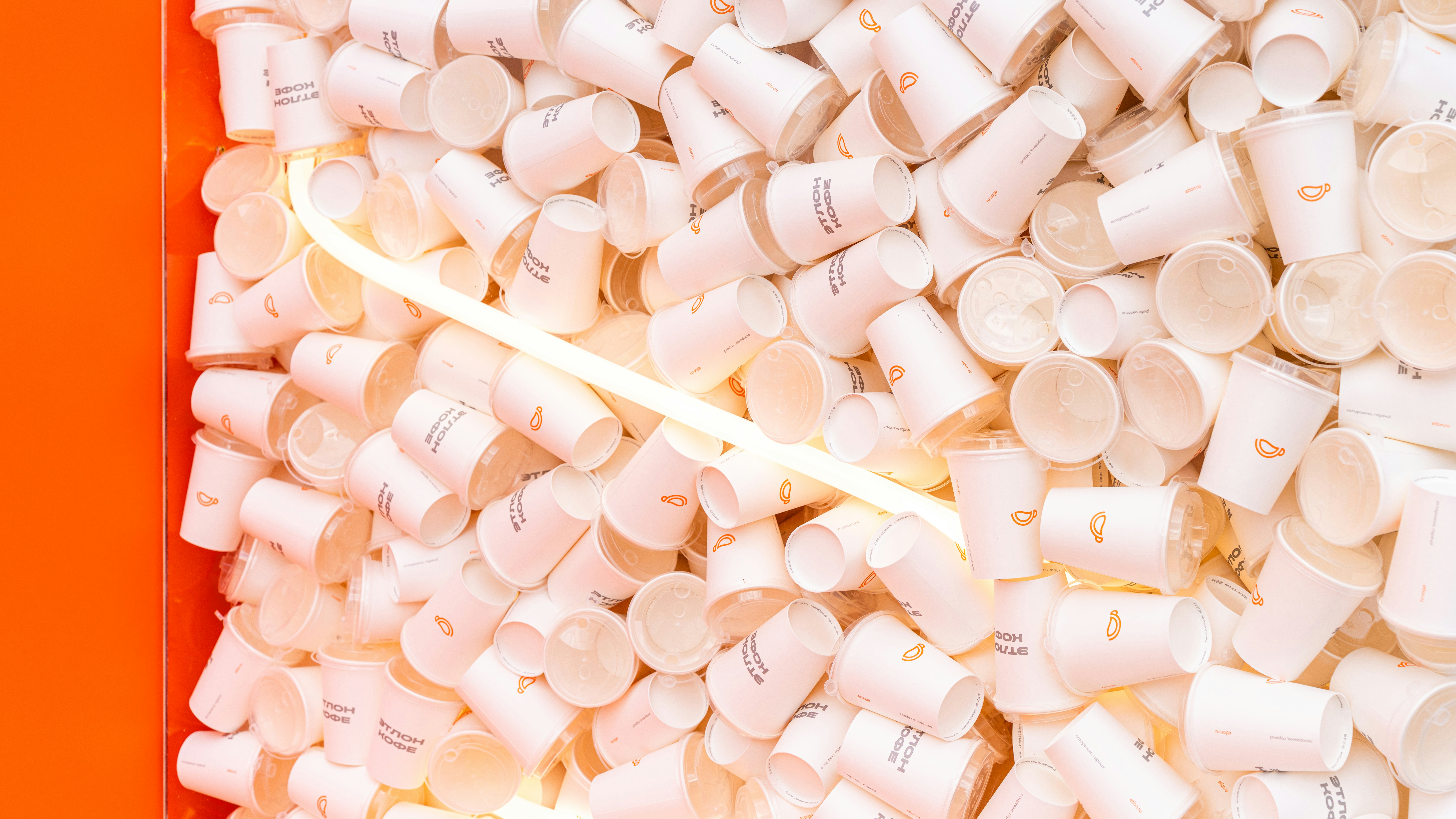 Pile of small white paper cups with orange border