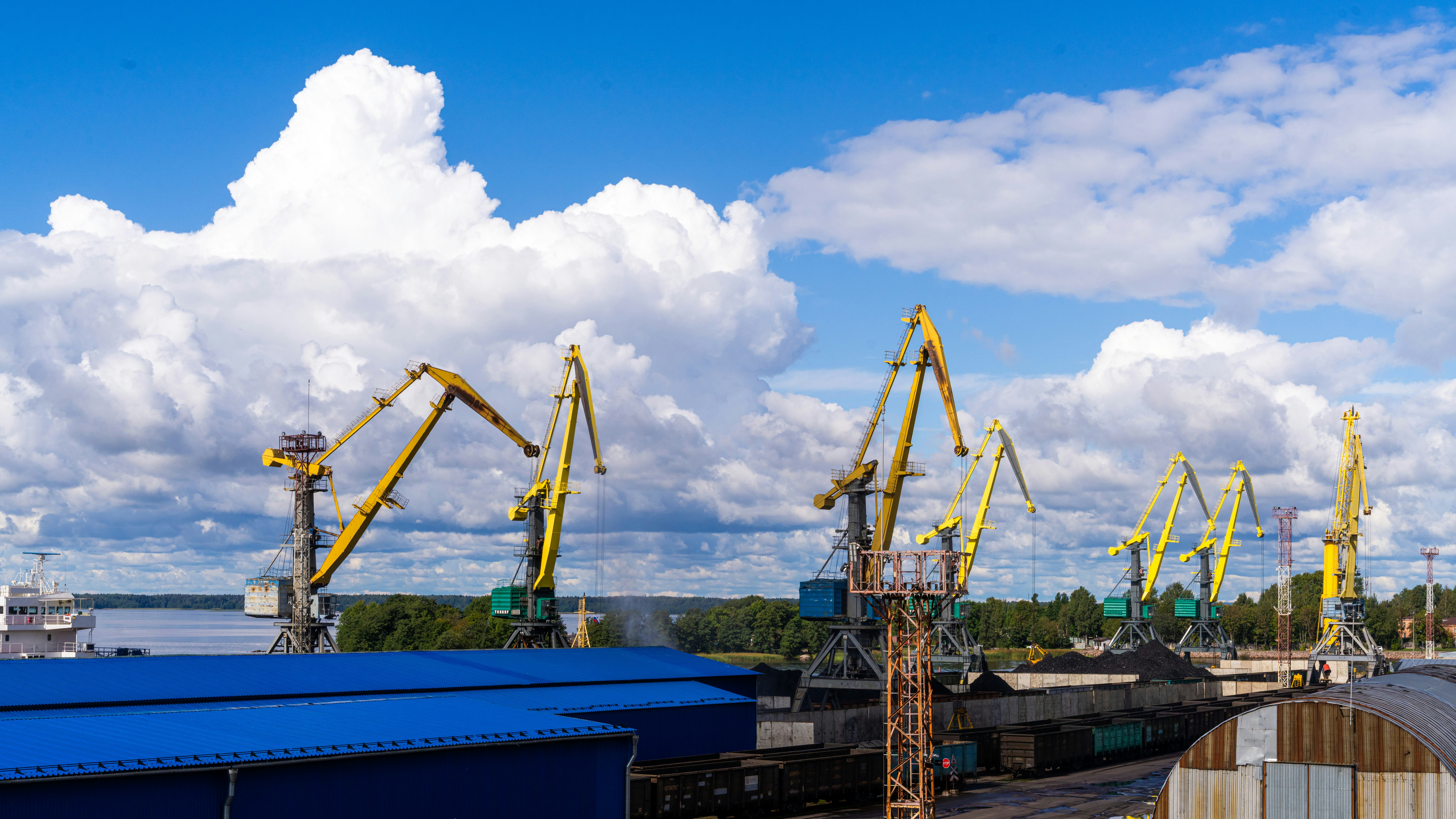 Industrial cranes at a port under a cloudy sky