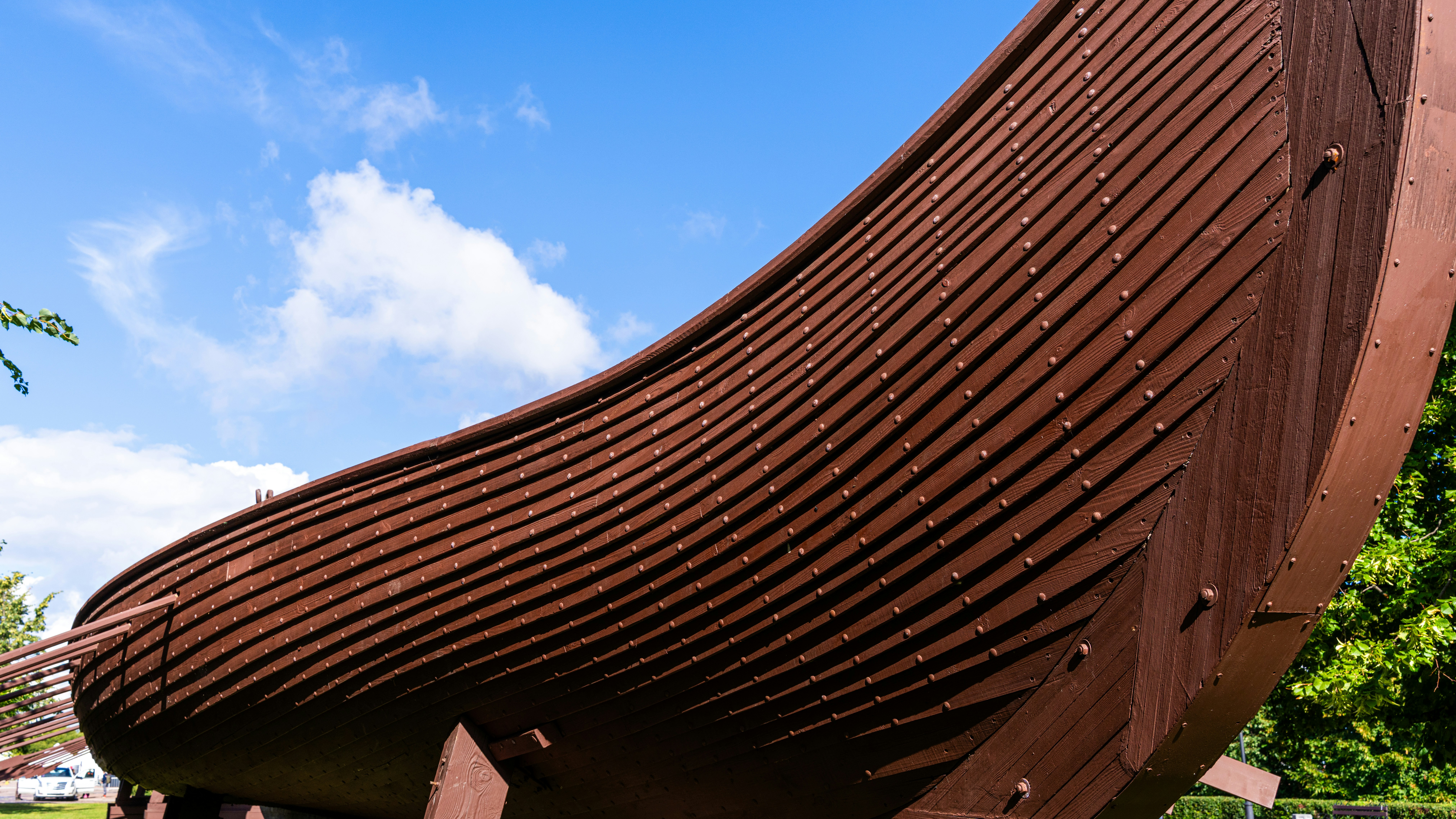 Rusted hull of a historic boat resting against a sunlit shoreline