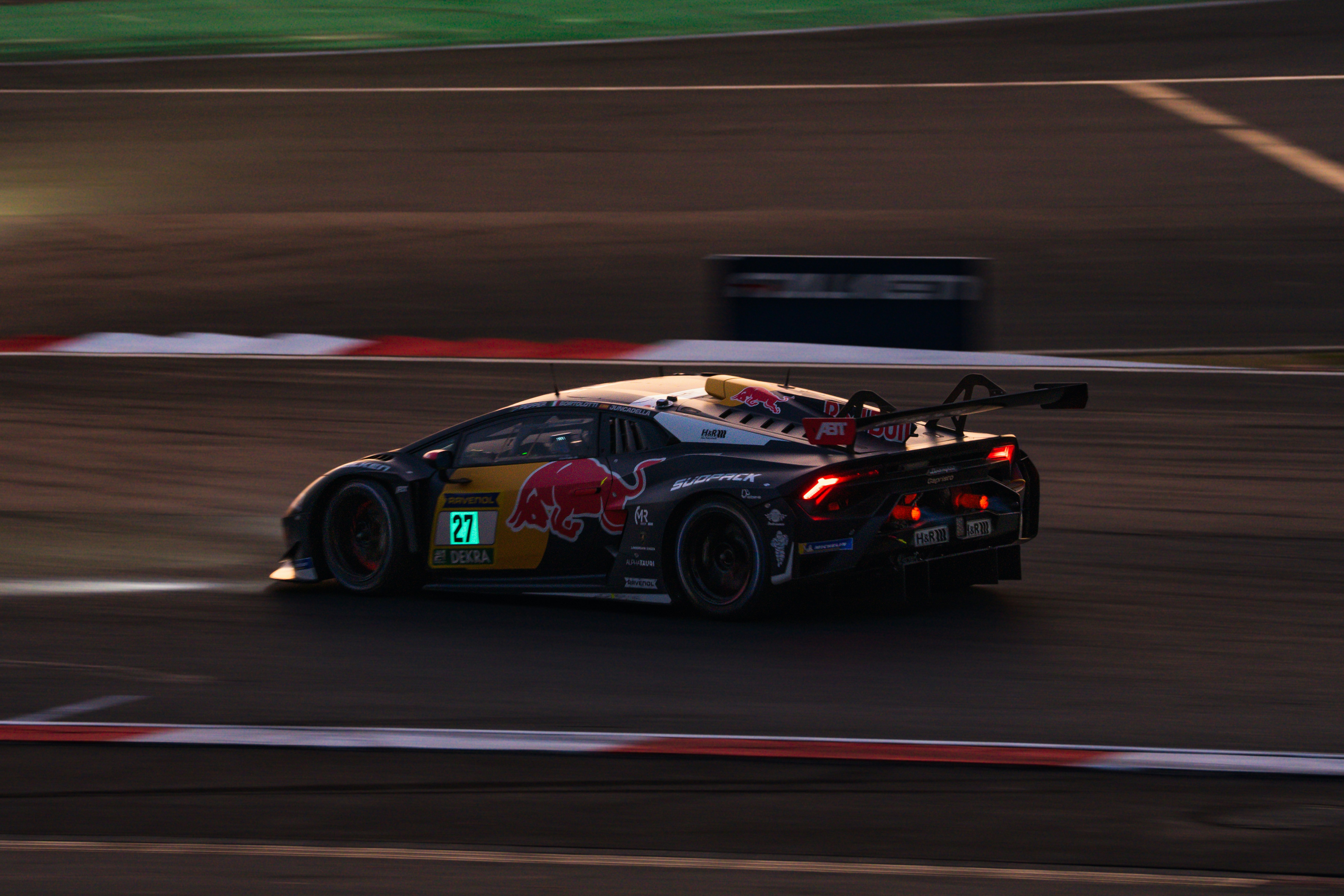 #27 - Red Bull Team Abt Lamborghini Huracán GT3 EVO2 --- If you consider downloading this image, a gentle reminder that any brands or logos depicted are protected by trademark. Please keep this in mind for your projects, especially if they are commercial — and thanks in advance for downloading! | Race car with red bull livery speeds on track.