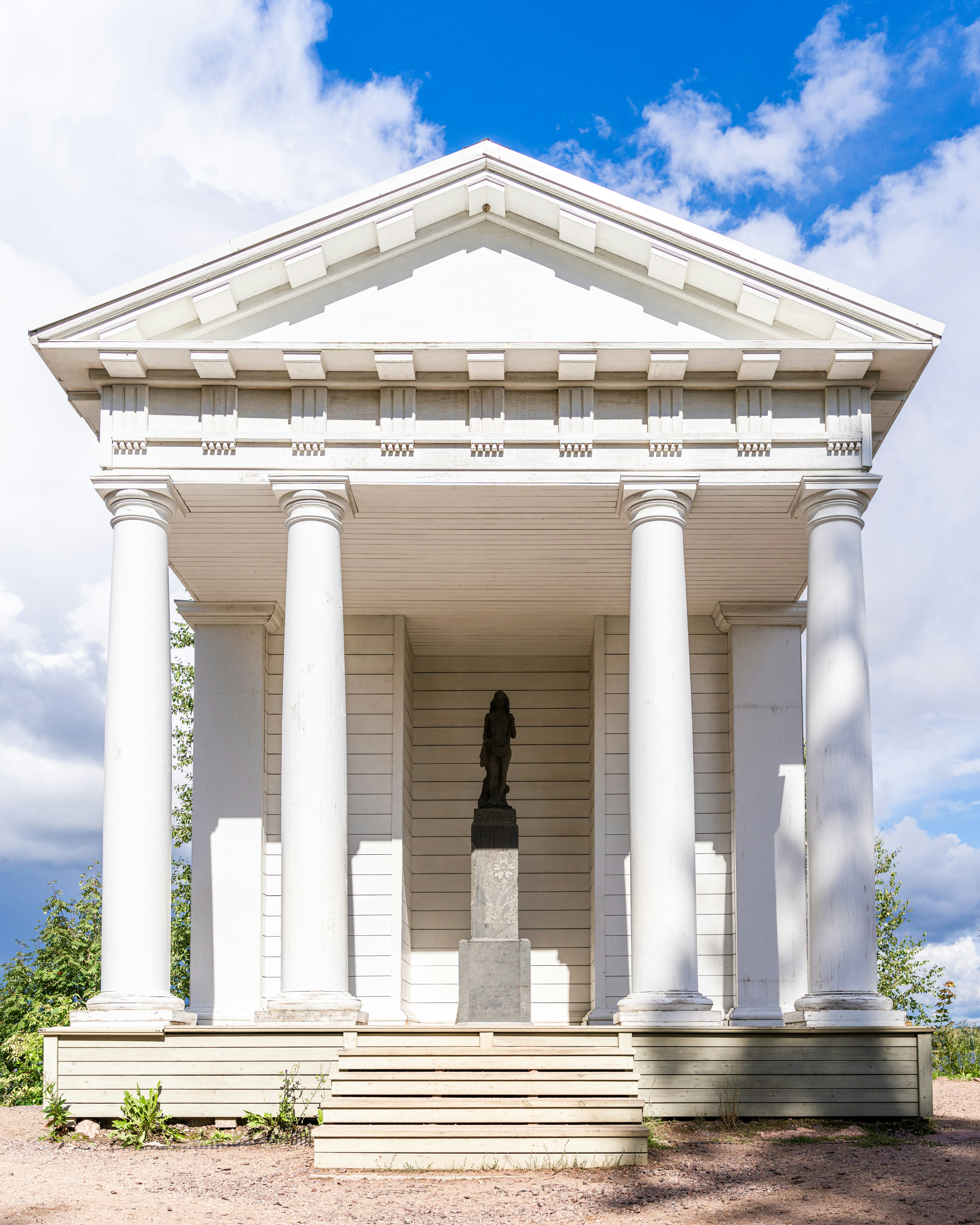 White neoclassical building with columns and statue.