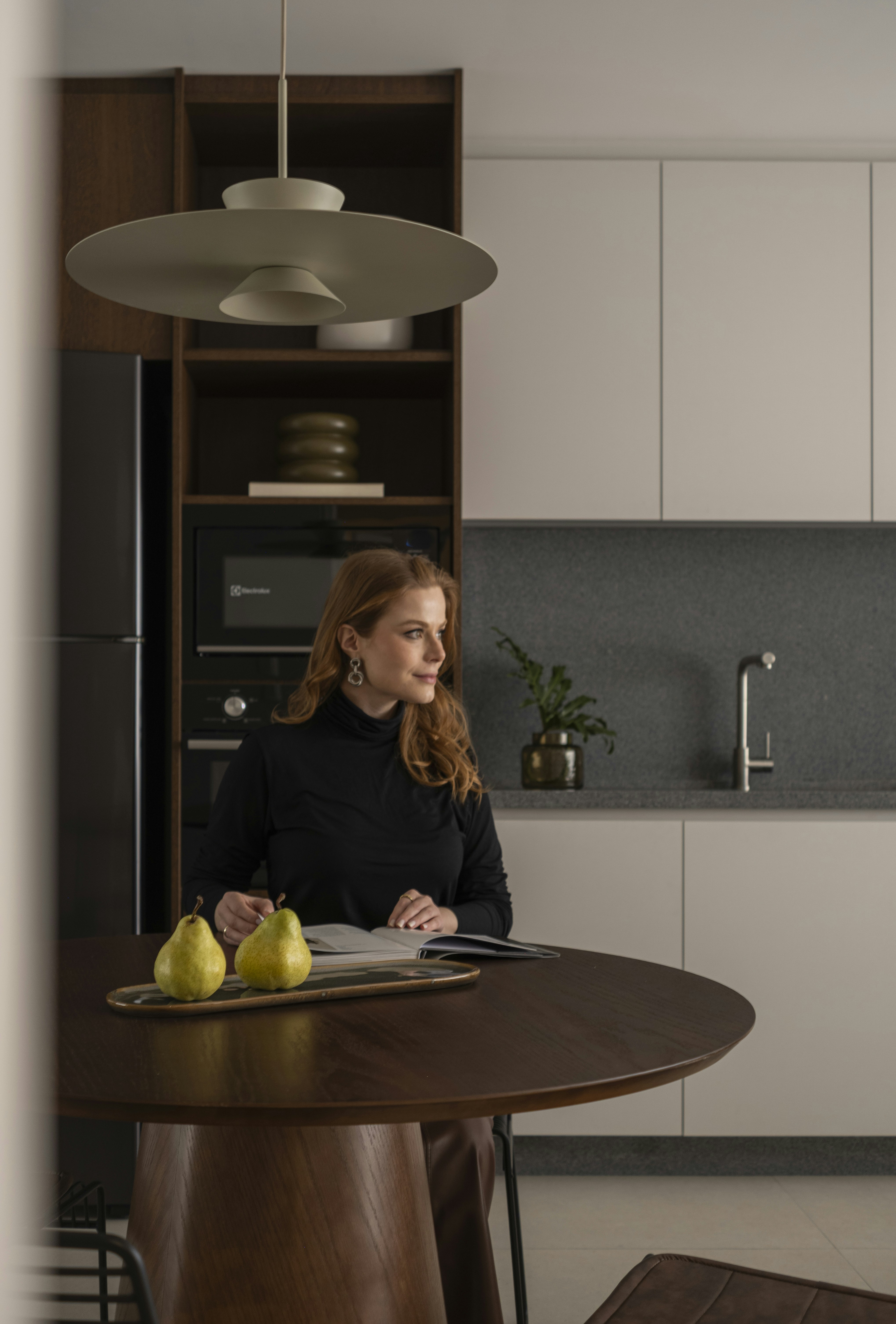 Fotografia para a Arquiteta Ísis Zaro Frighetto. | Woman in a modern kitchen with pears on table.