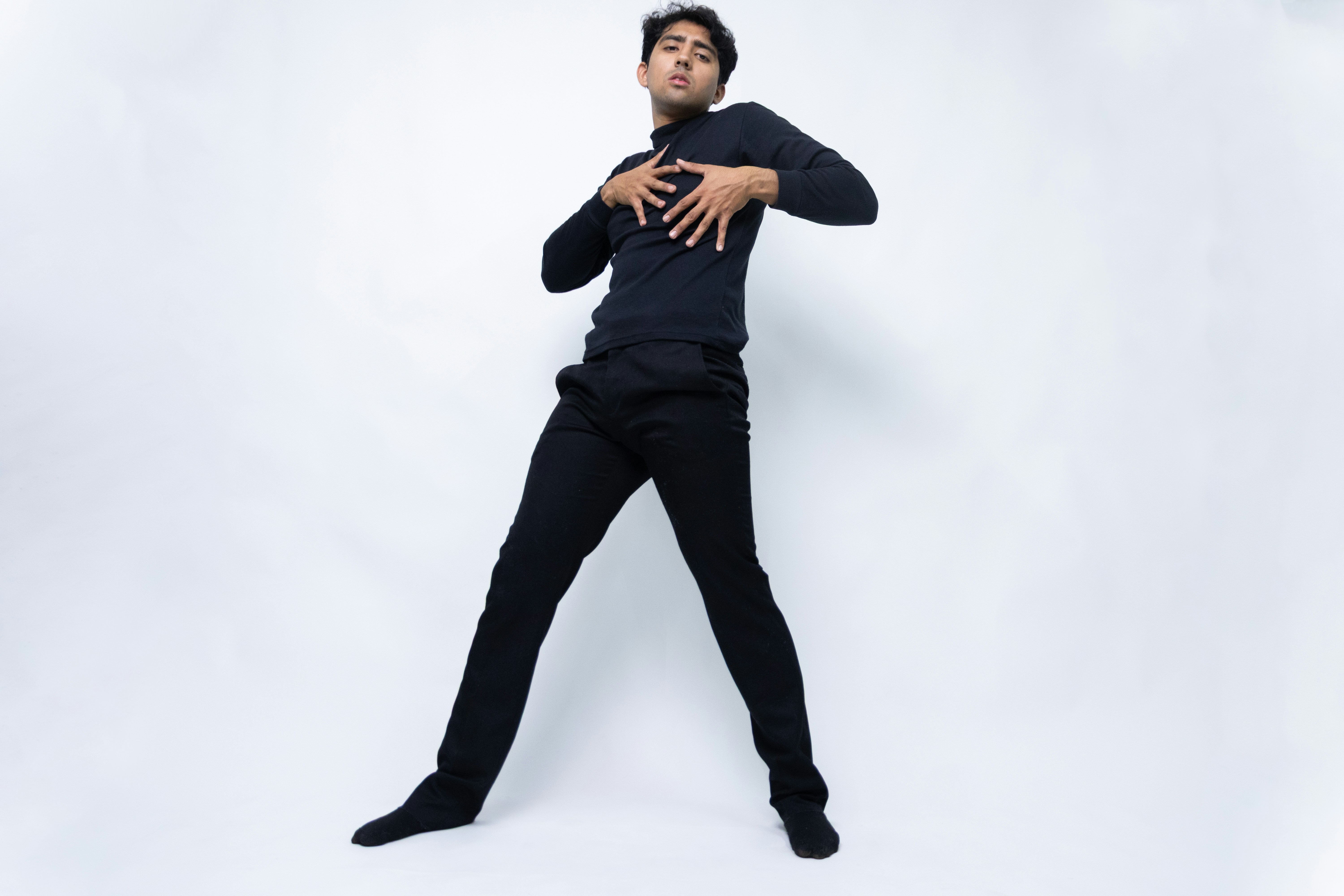 A man in black clothing striking a dramatic pose. photo – Free White ...