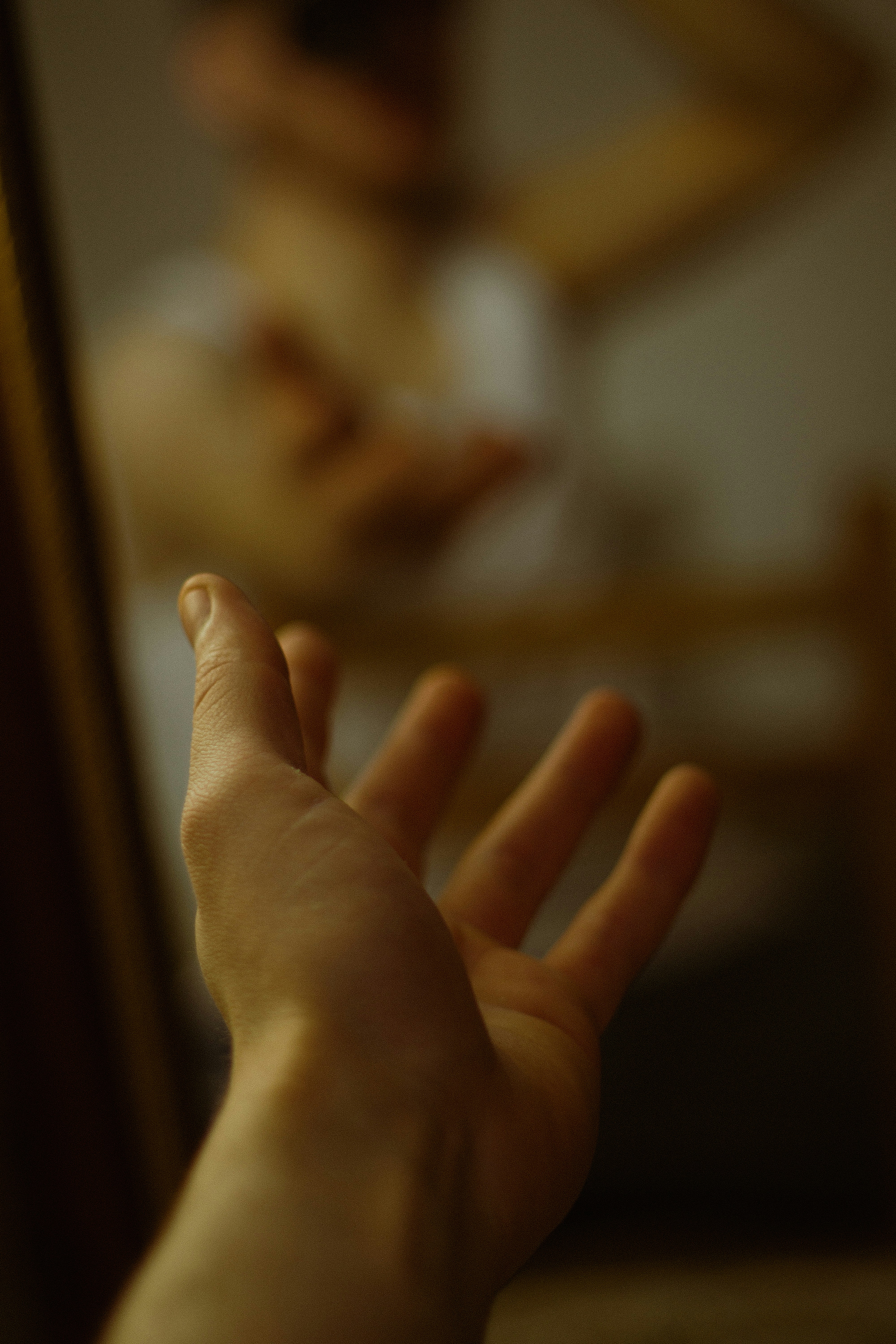 Hand reaching out towards a blurred reflection