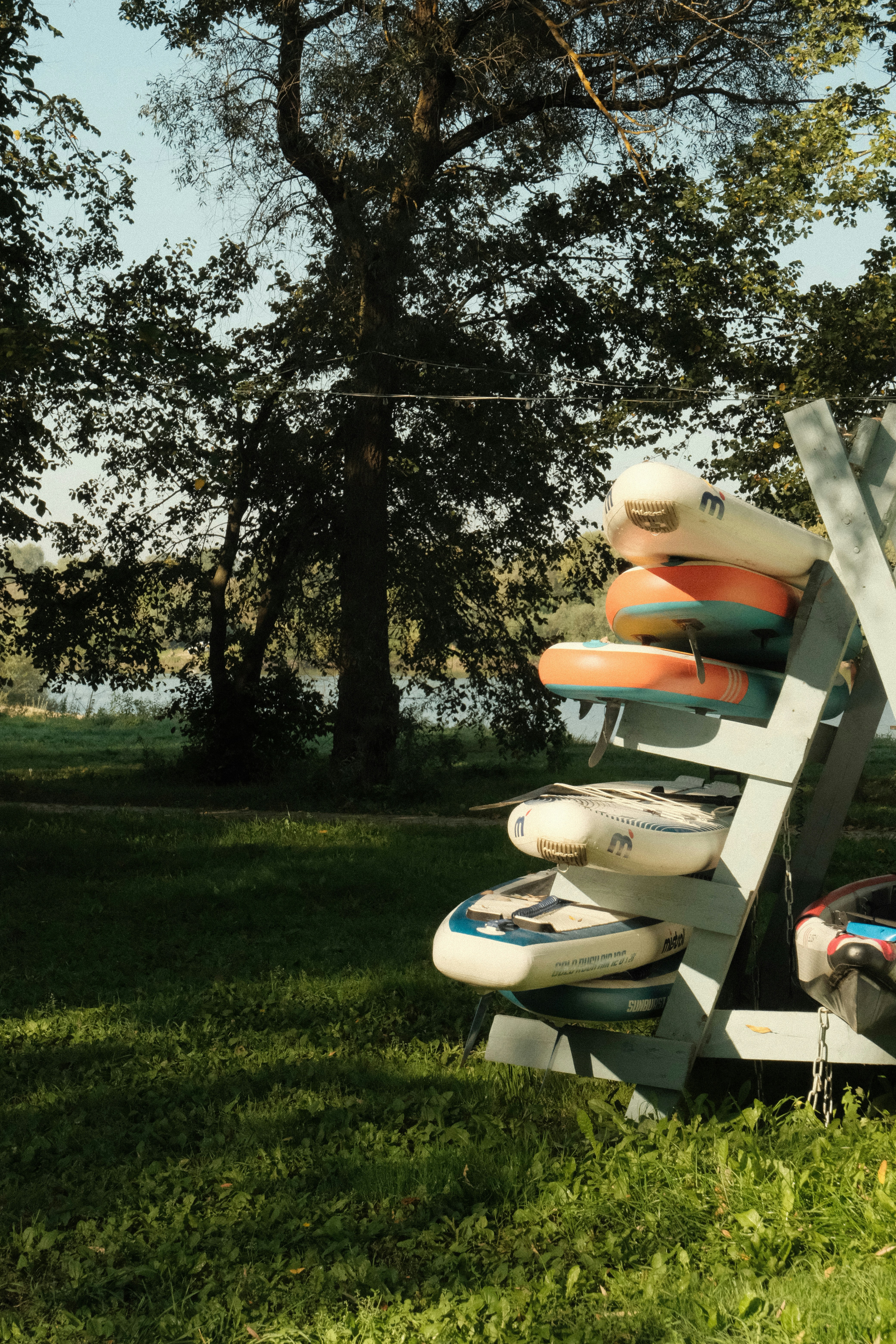 Dappled Sunlight on a Kayak Stack by the Meadow