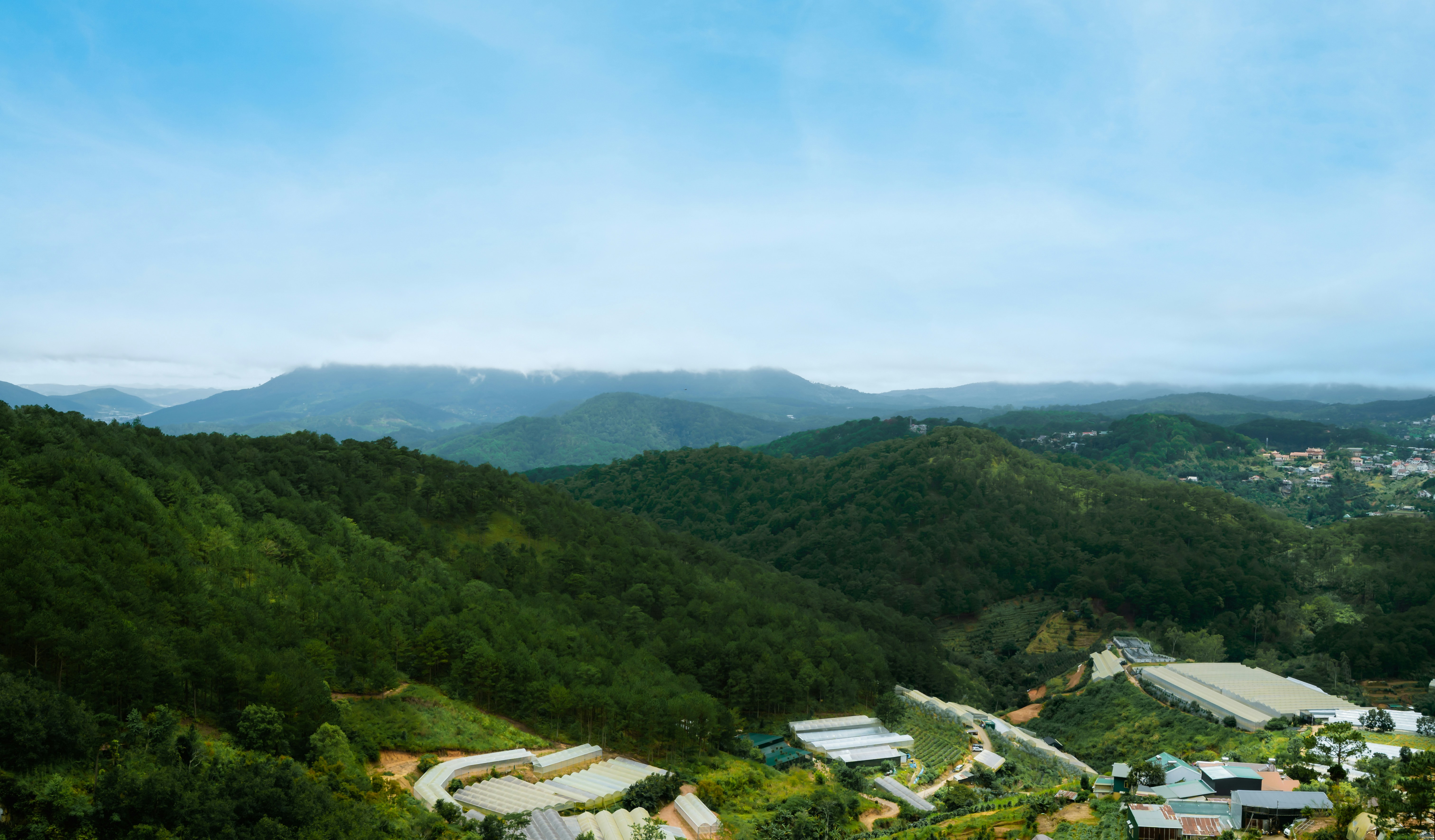 Rolling green hills with scattered buildings under a blue sky.