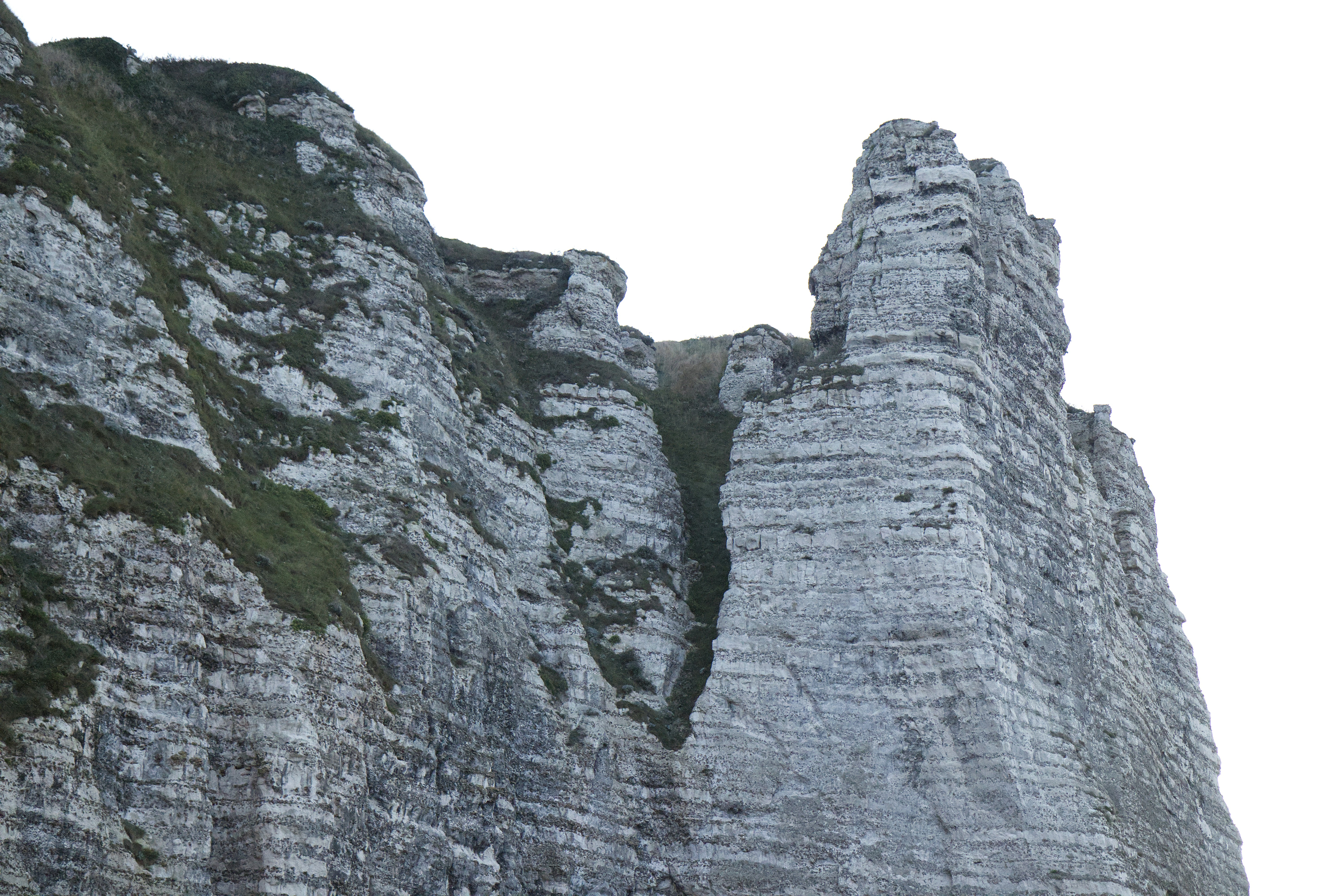 Tall, jagged rock formation against a white sky