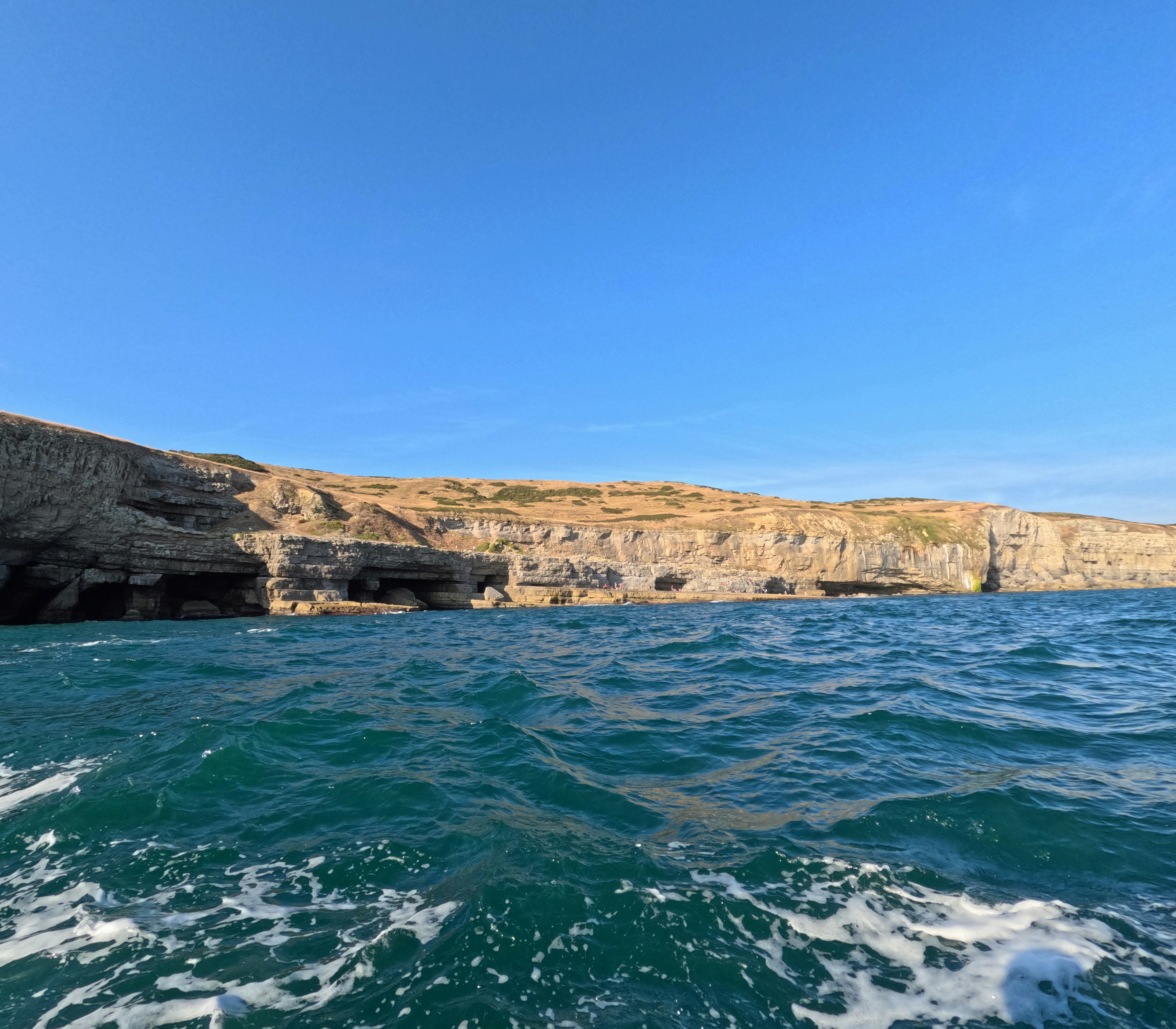 Cliffs and caves along a rocky coastline with blue ocean.