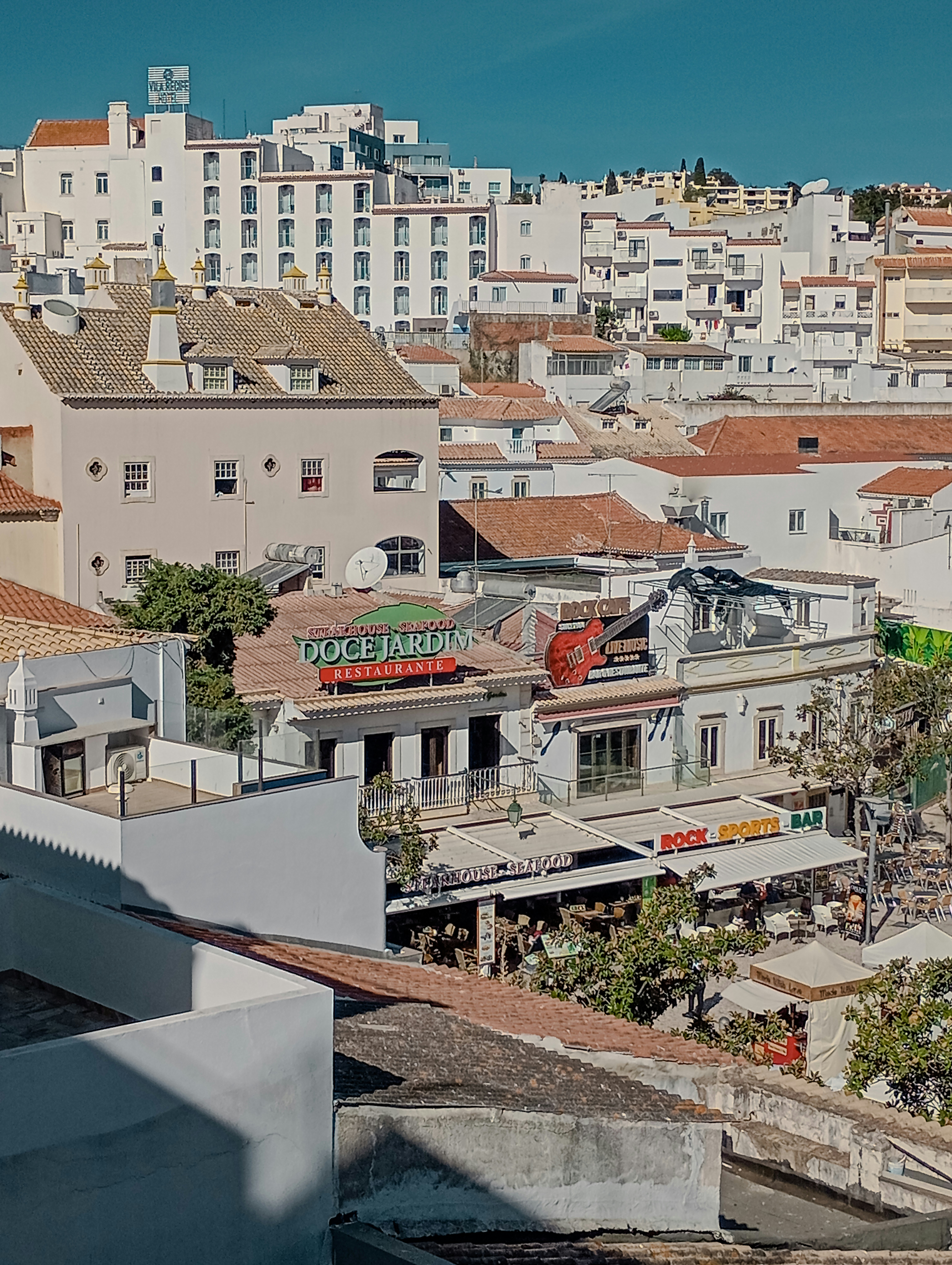 Vibrant scene showcasing rooftops and bustling eateries in a lively urban setting. The image highlights the charm of local architecture and outdoor dining.