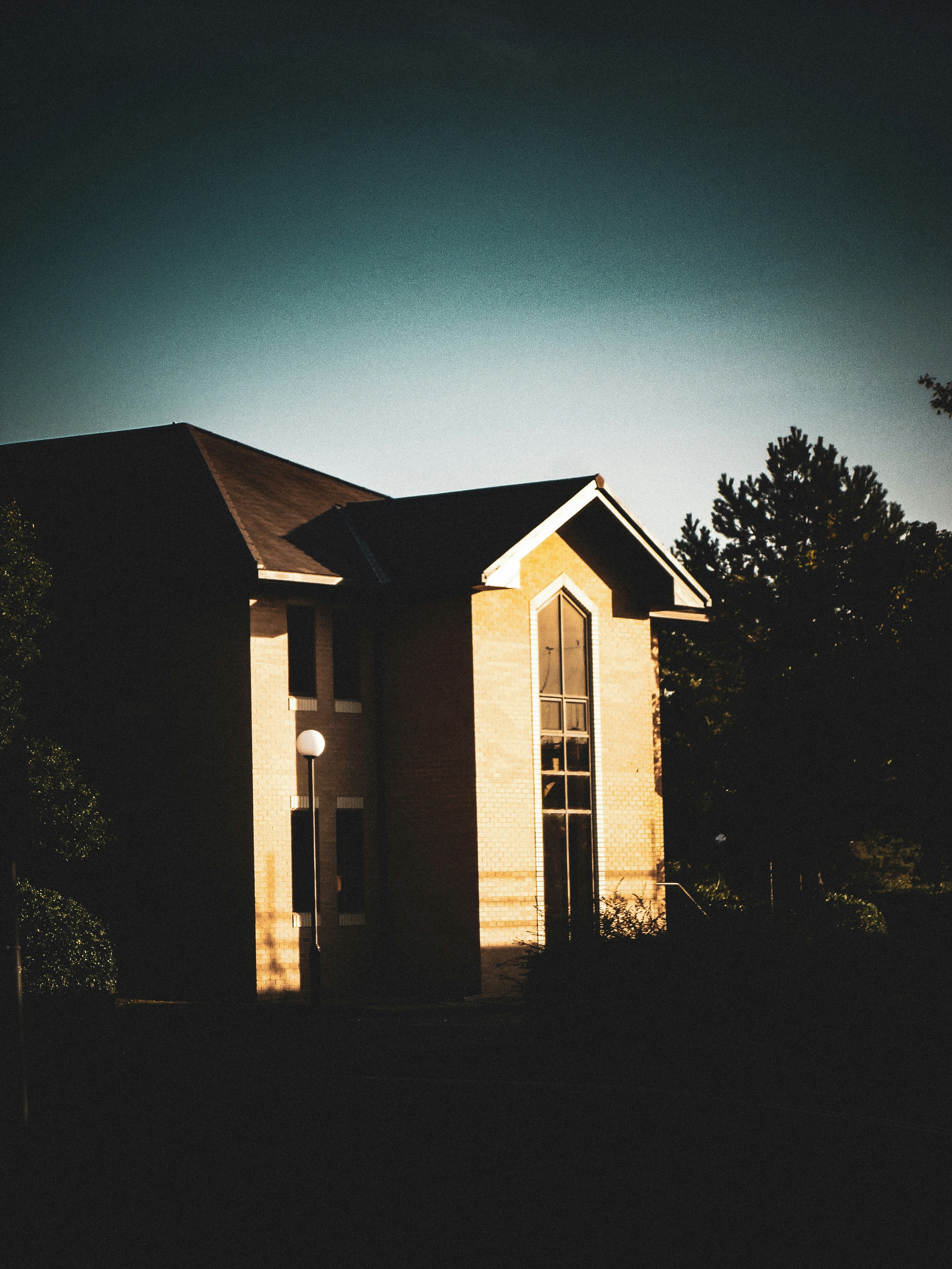 A brick building with a large window at sunset.