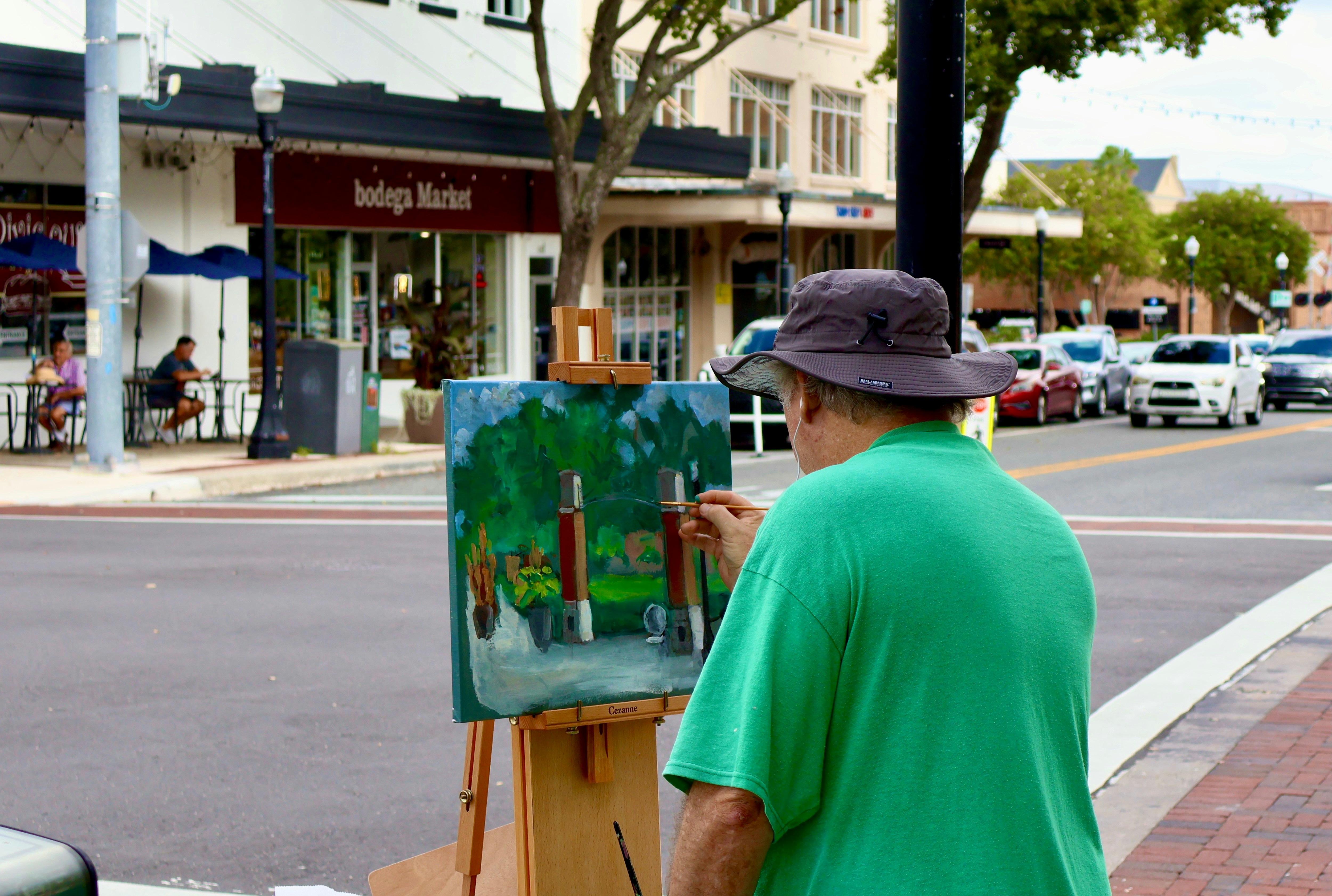 Man painting outdoors on a street easel