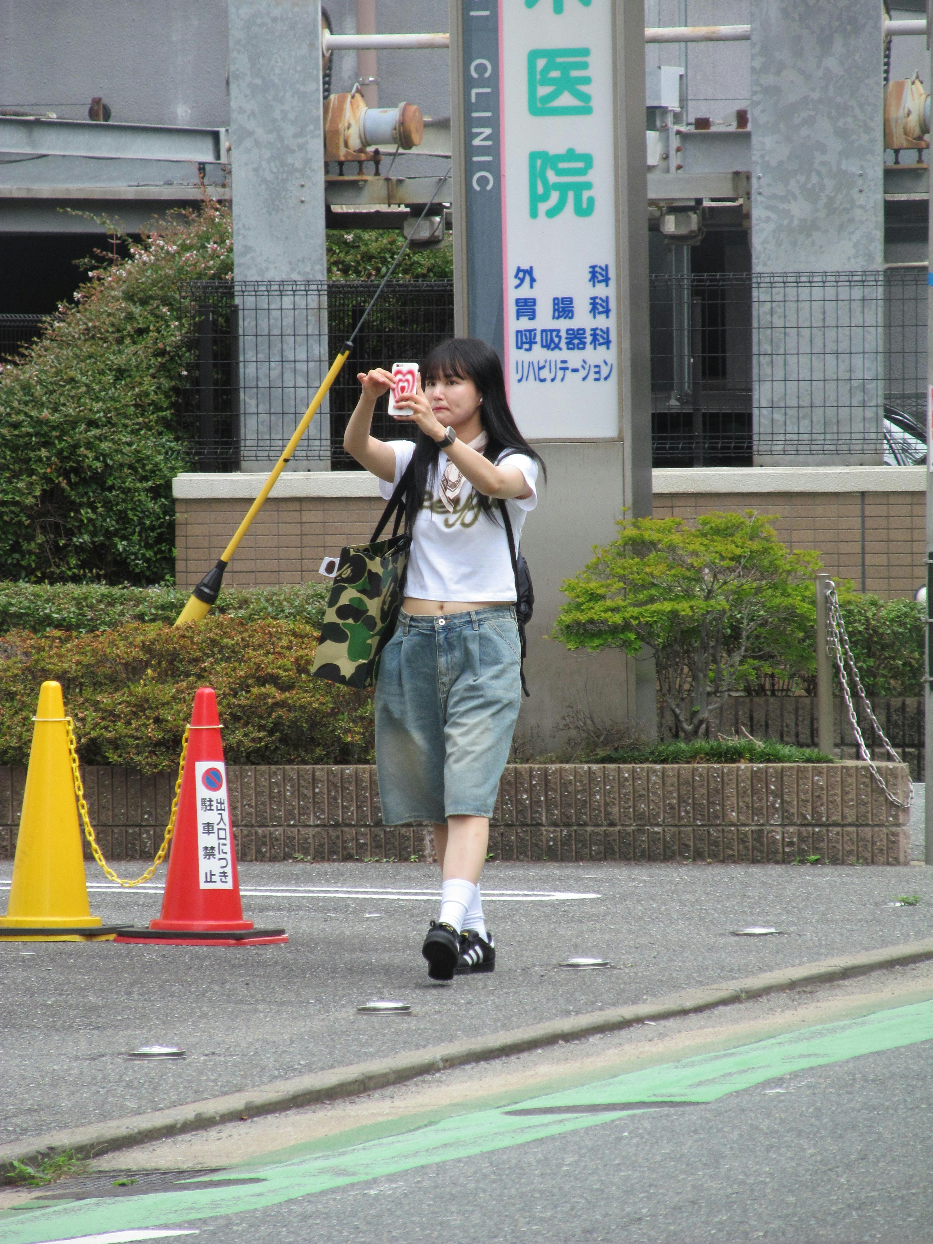 Young woman taking a selfie with phone outdoors.