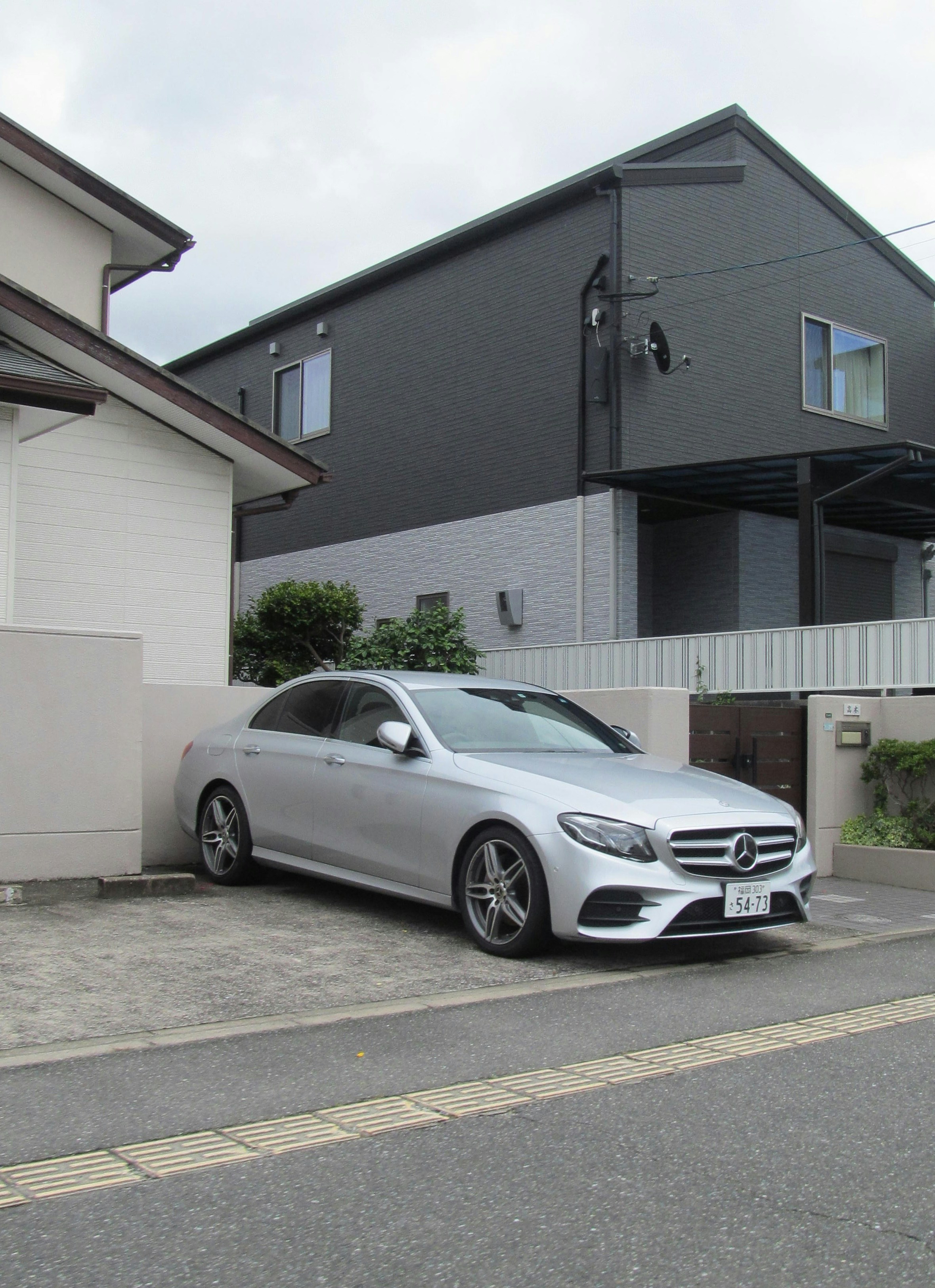 A sleek silver Mercedes-Benz parked beside contemporary residential buildings, showcasing a blend of luxury and modern design.