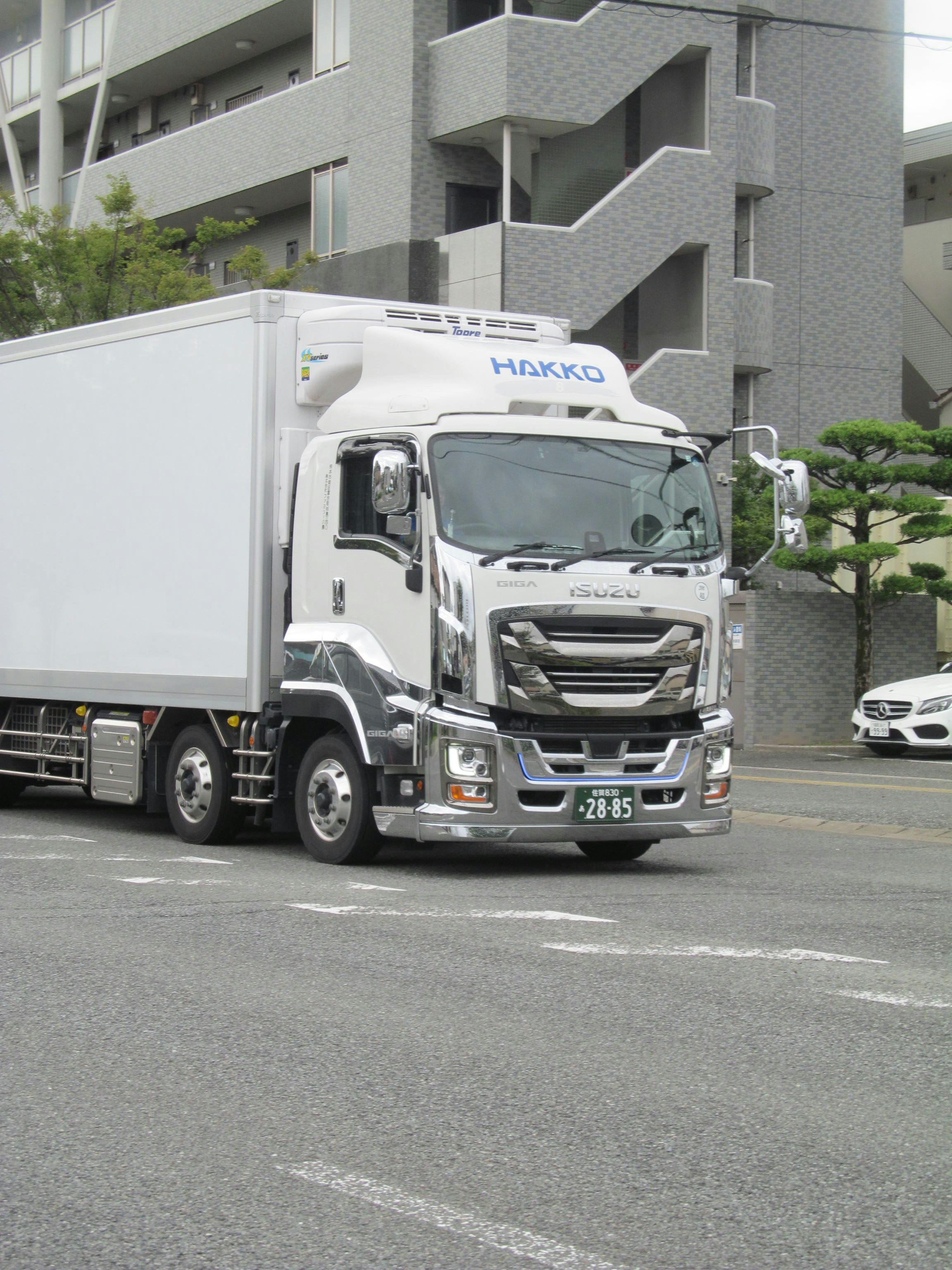 White delivery truck with chrome accents on road.