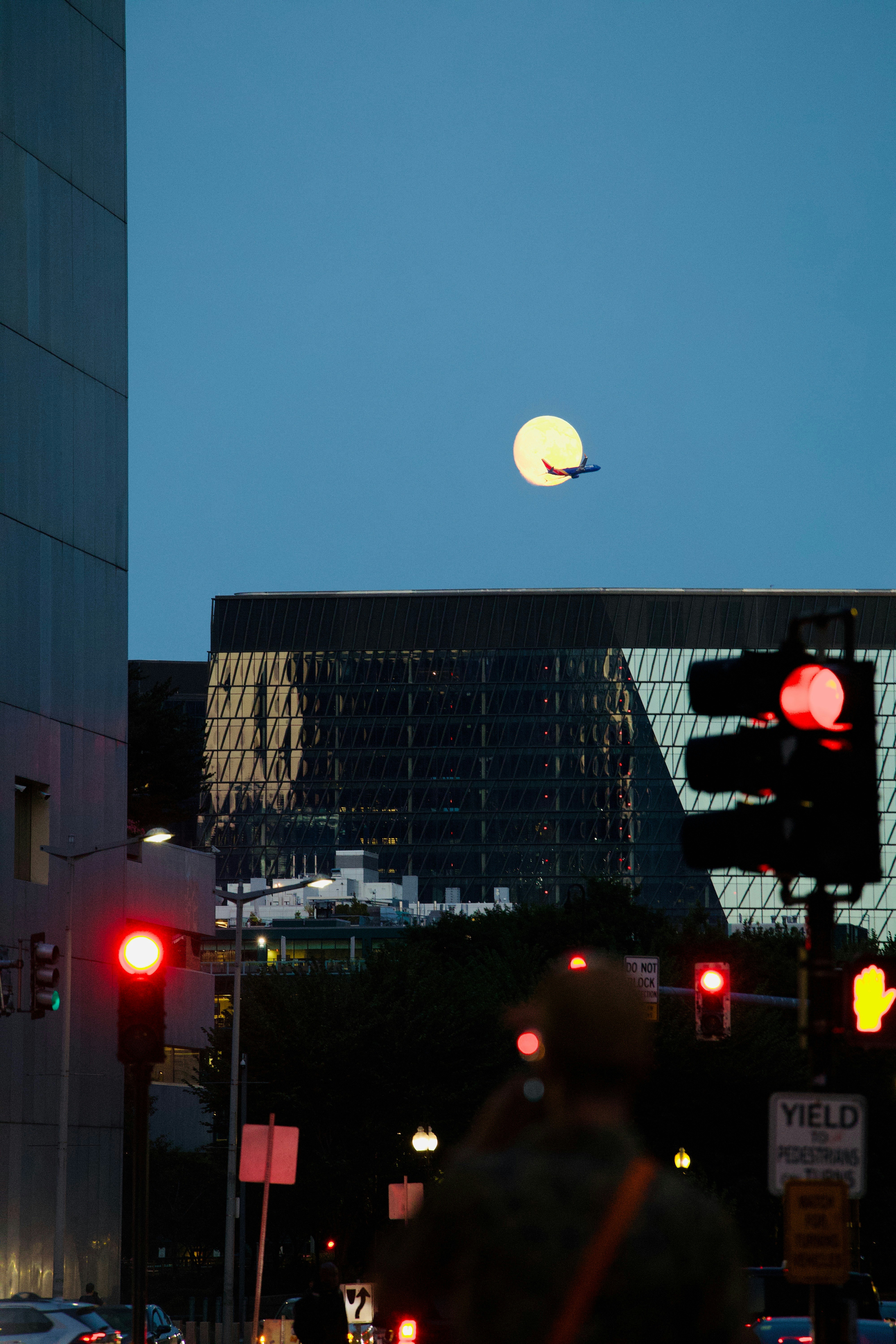 Moonbound Crossing: A Tiny Jet Fleetingly Traces the Moon Over a City Street