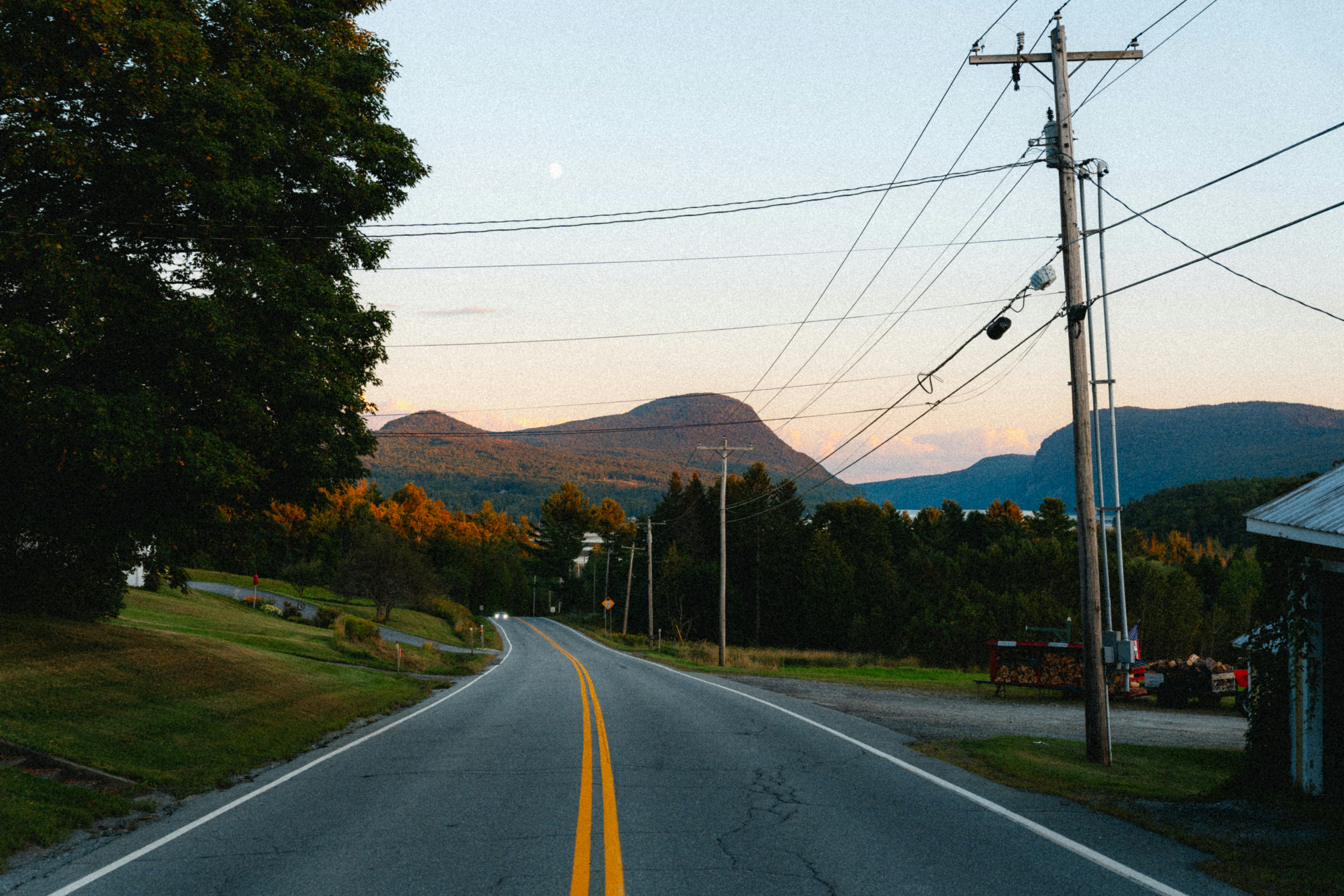 Empty road leads to distant mountains at dusk.