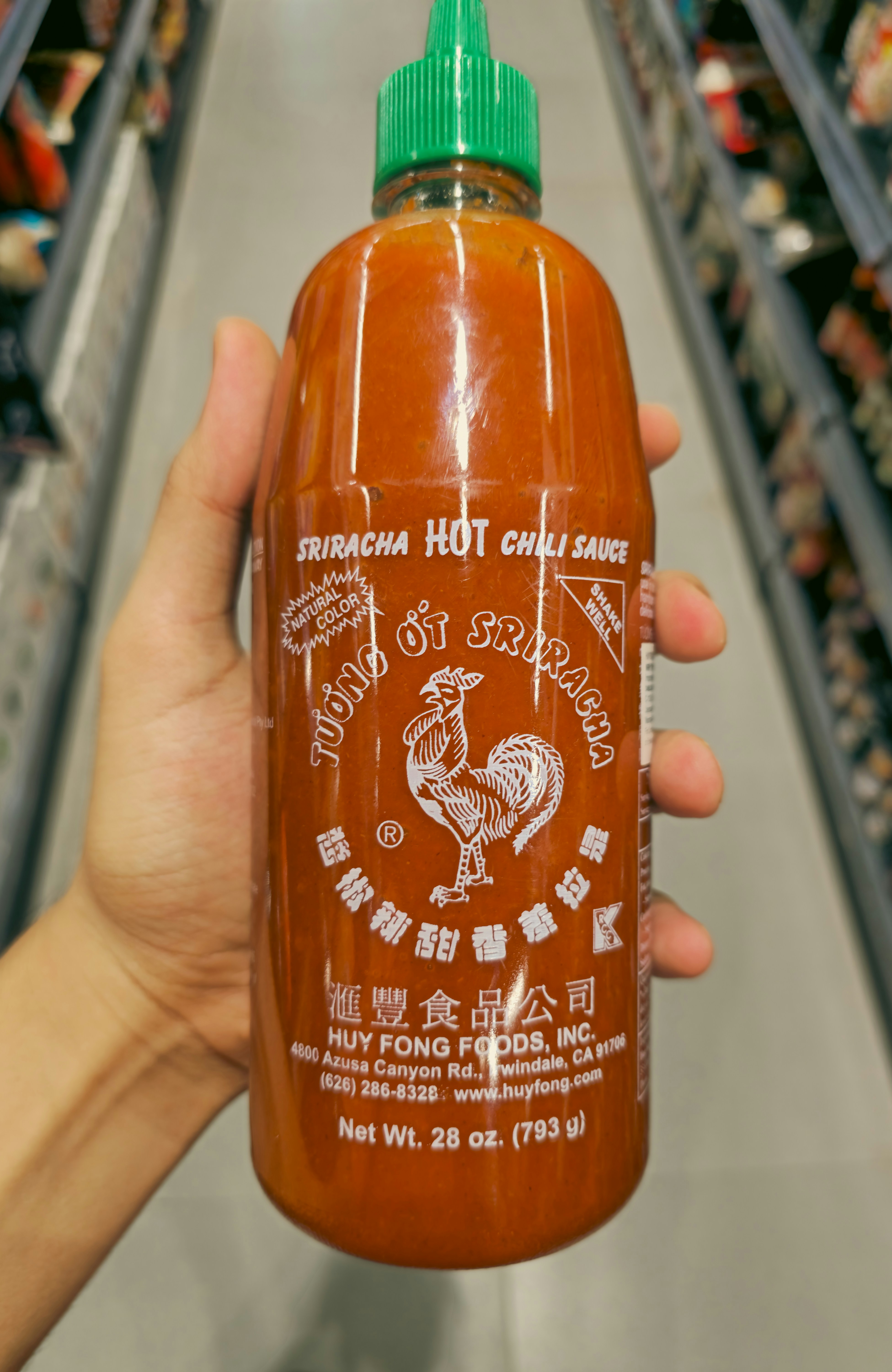 Green Cap, Red Heat: Sriracha Bottle in Aisle Light