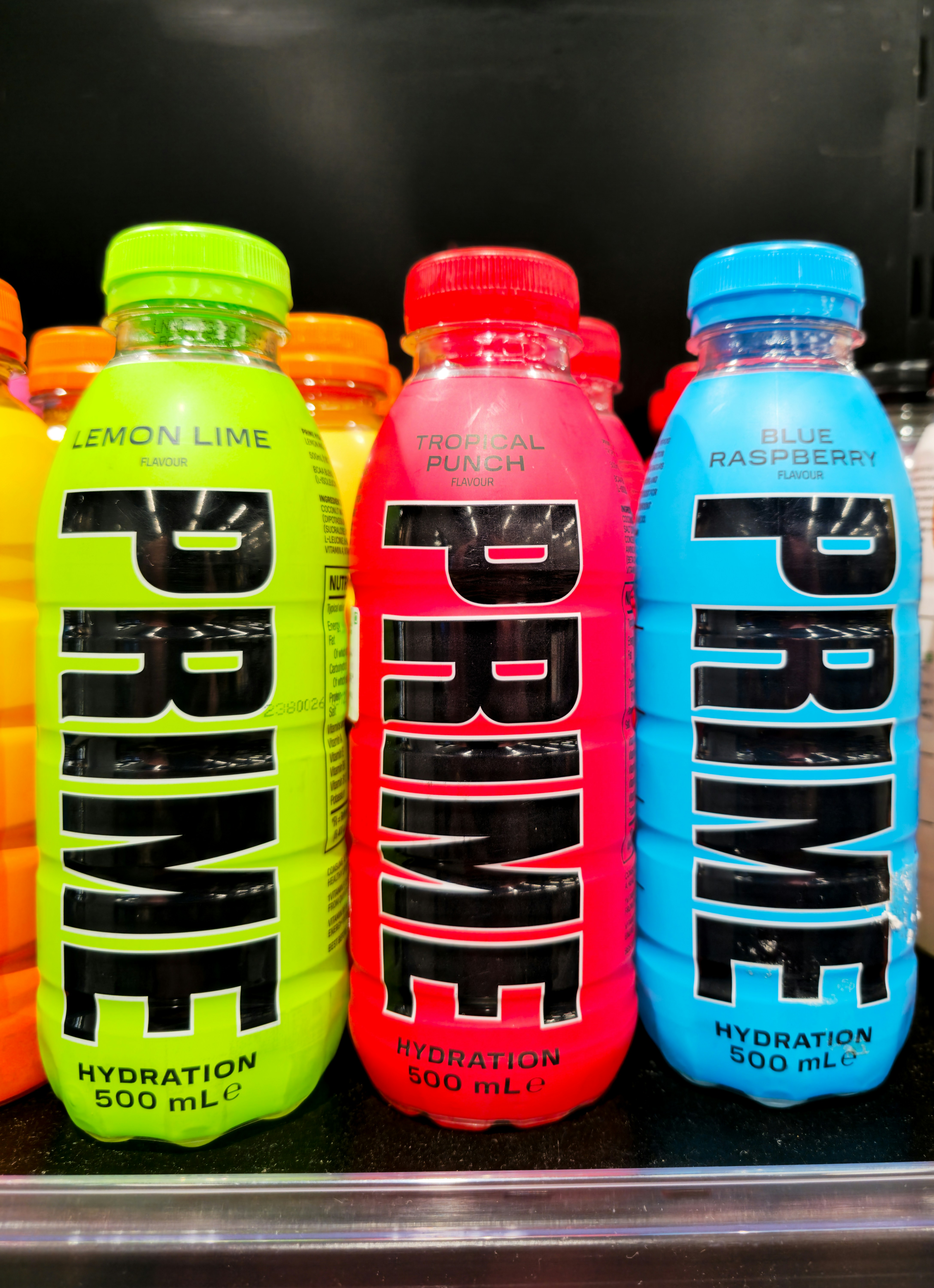 Neon Hydration Trio: Bold Bottles Align on a Grocery Shelf