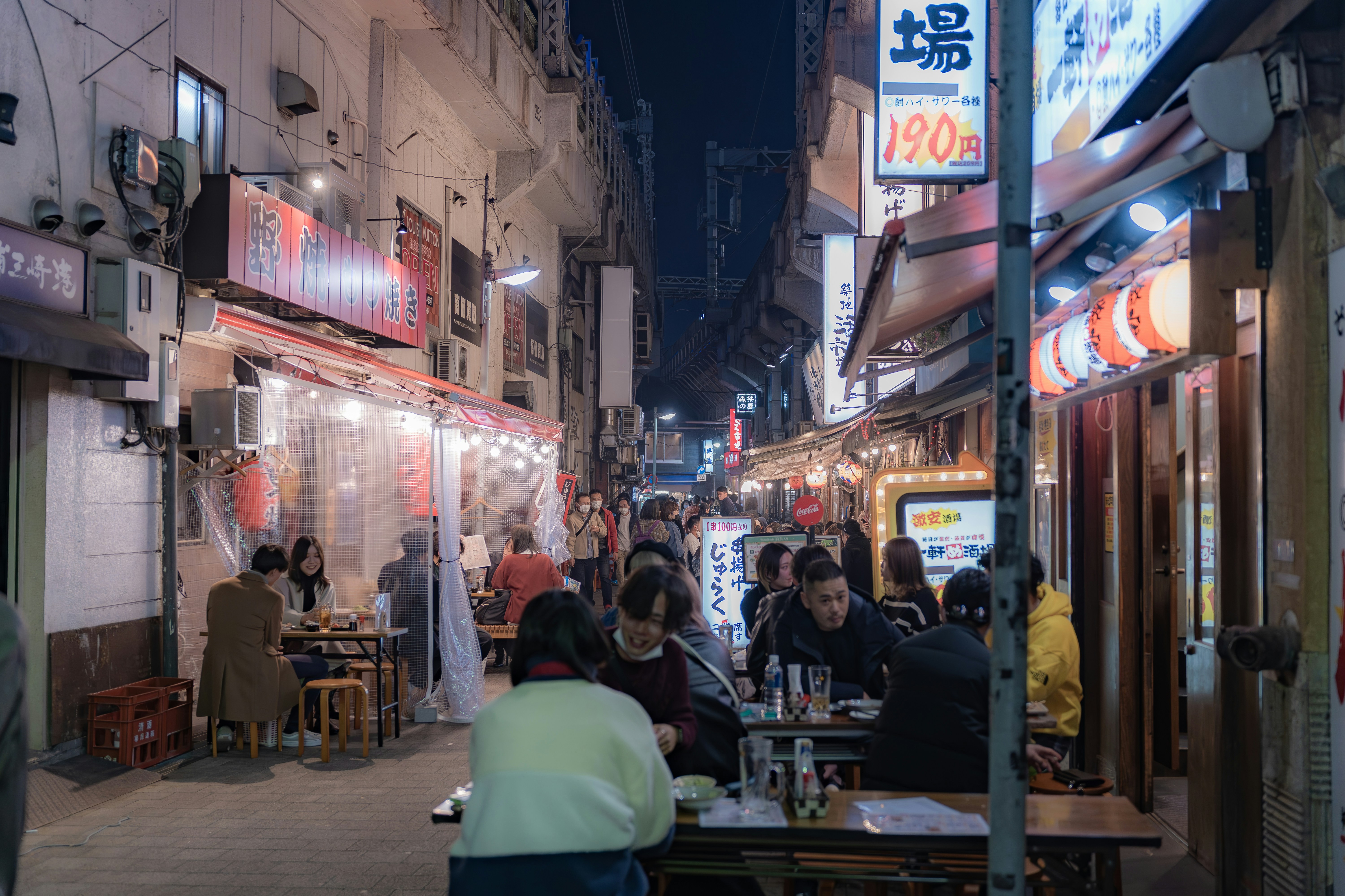 People dine at outdoor tables on a narrow street.