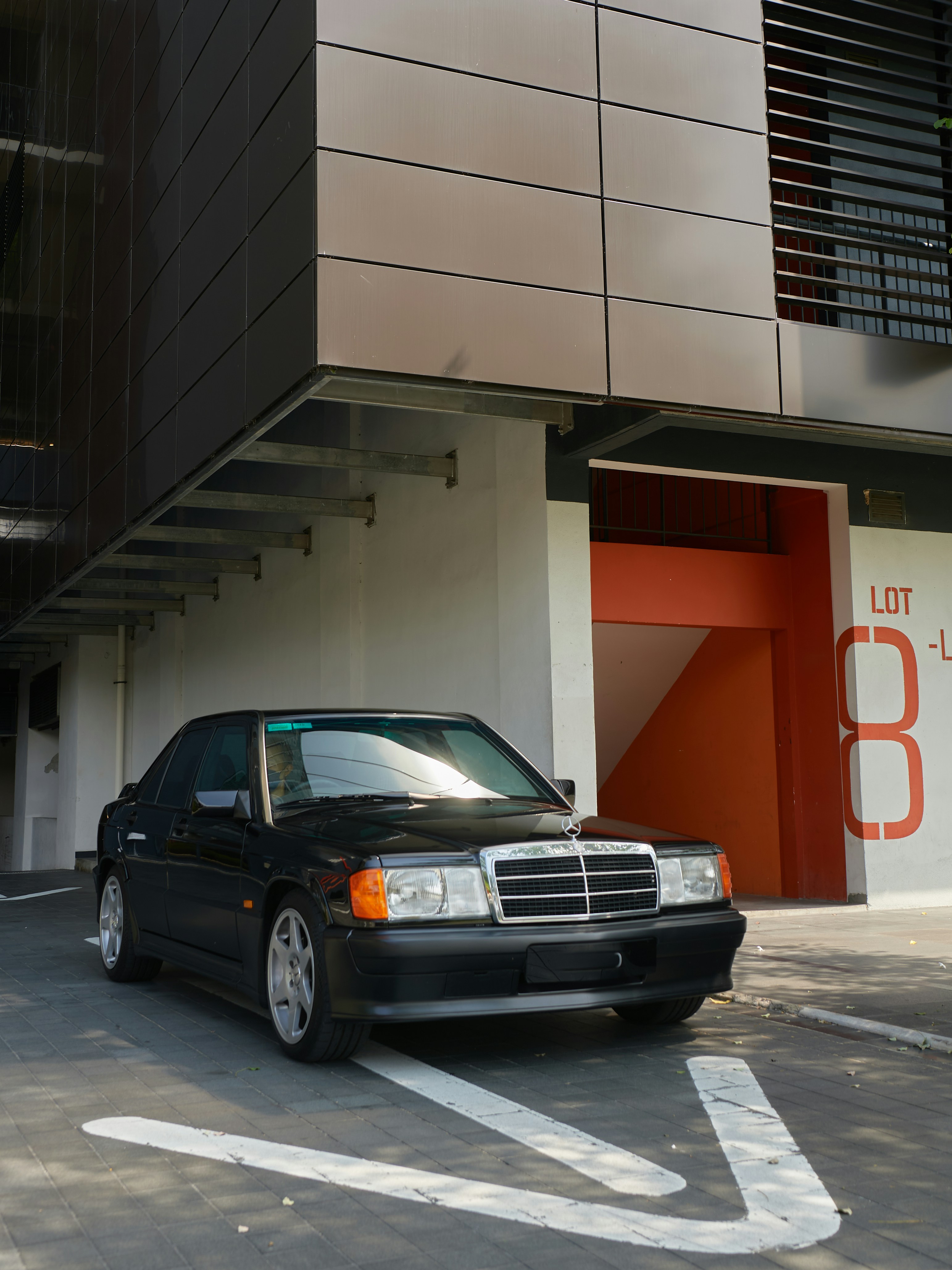 Black Sedan in Urban Parking Under Modern Architecture