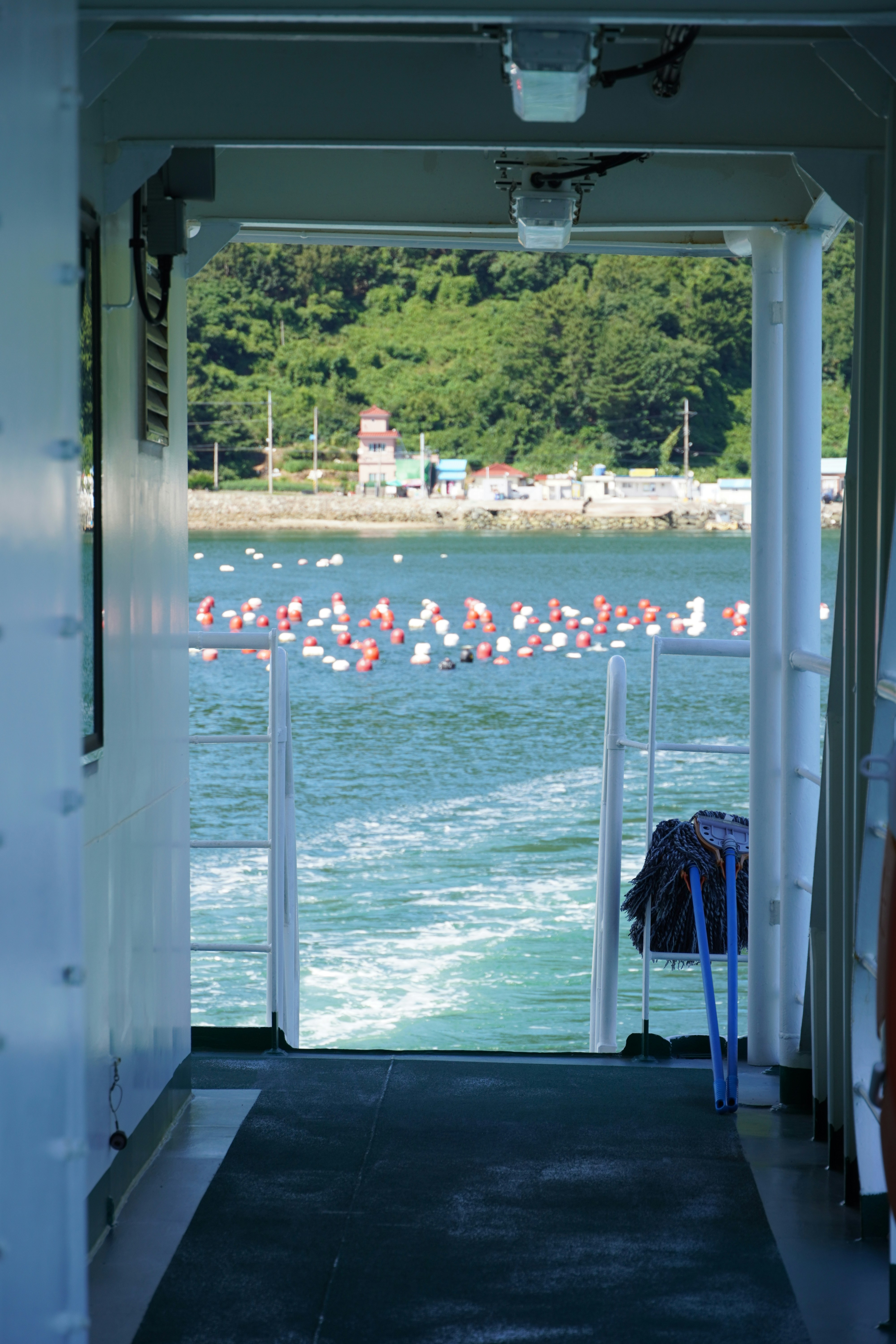 Buoys Across the Blue: A Corridor of Color Framed by a Boat Hatch
