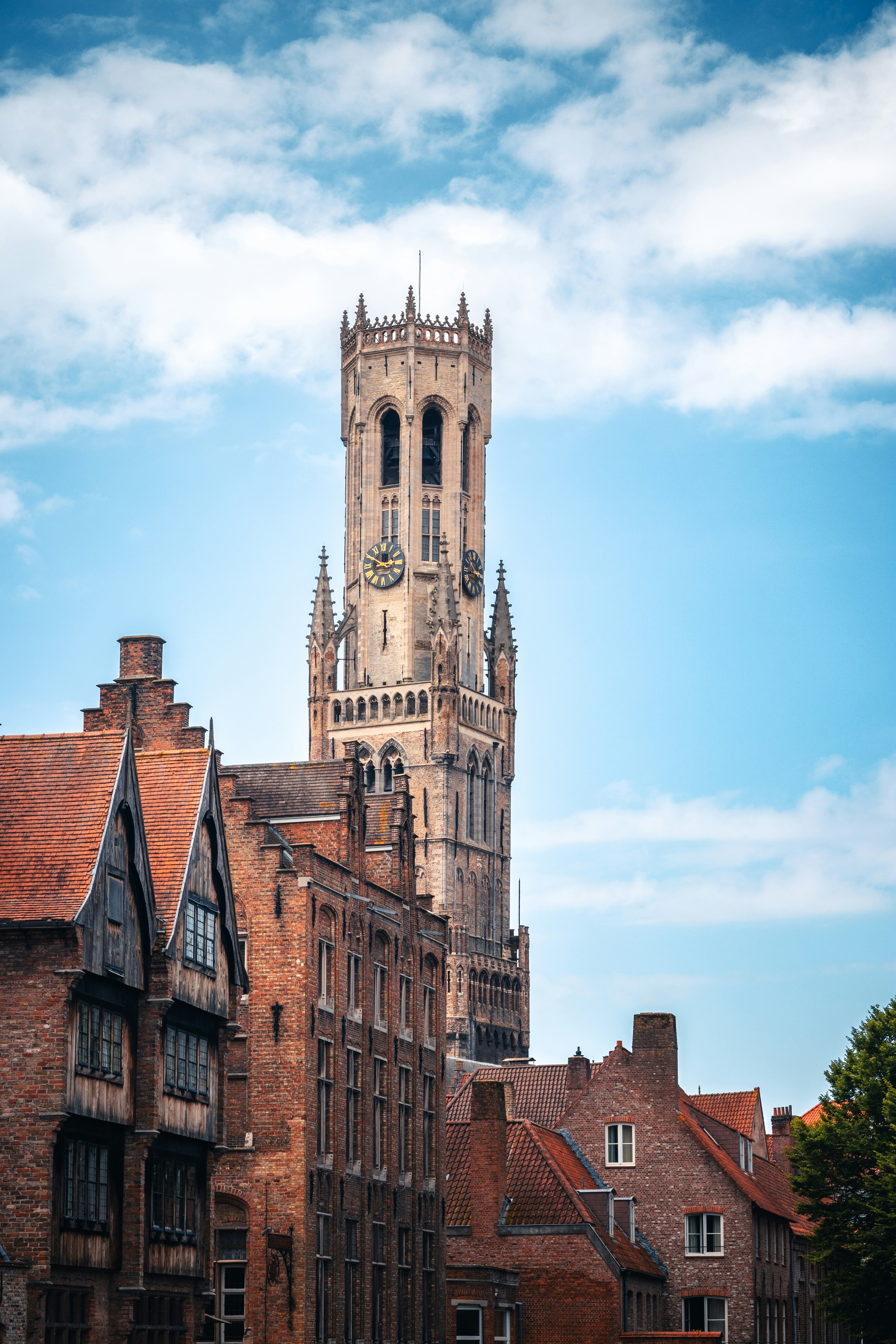 The heart of Bruges, standing tall... | Historic tower and buildings under a blue sky.