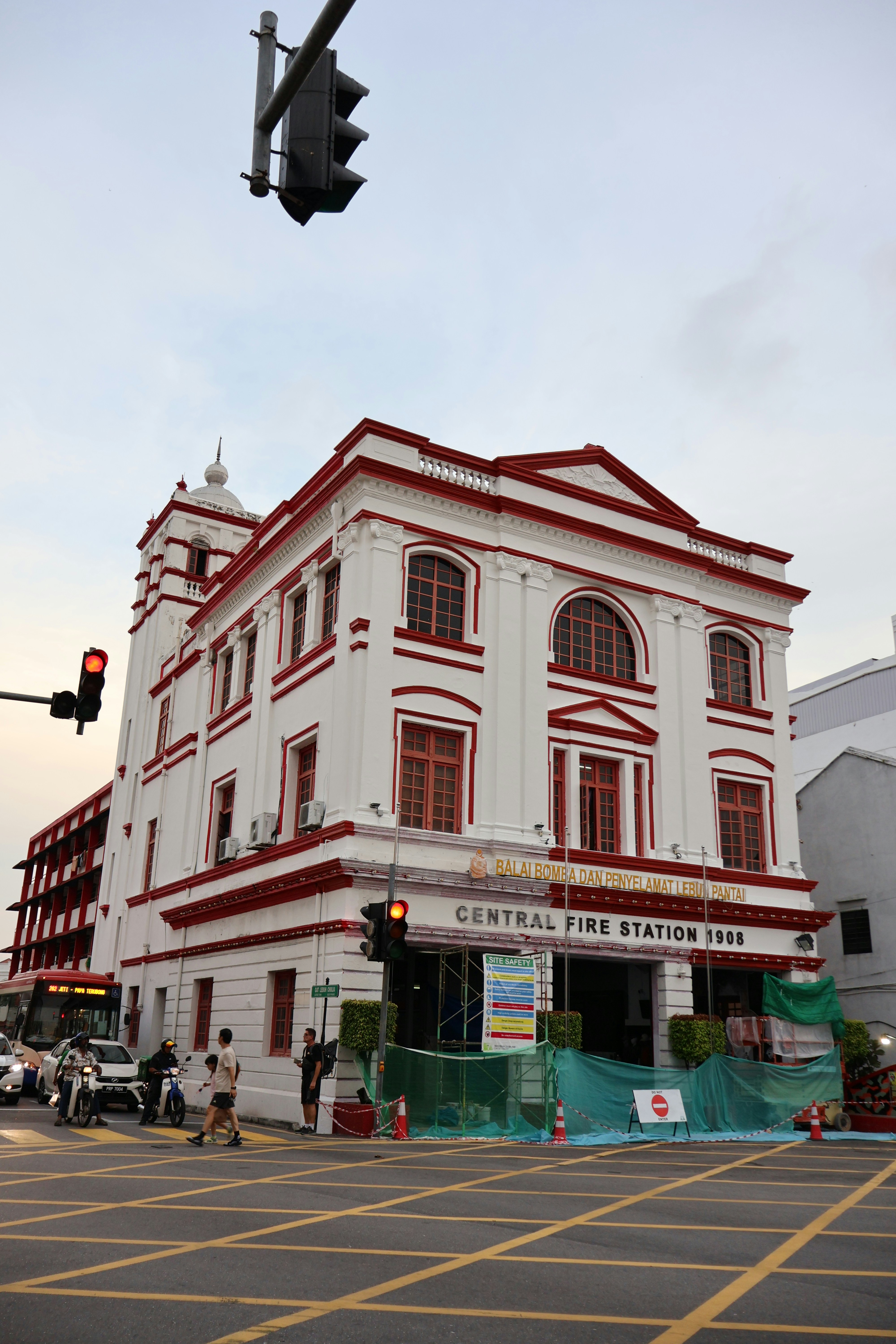 Historic Central Fire Station showcasing colonial architecture with striking red and white details. Traffic signals and urban elements frame the scene.