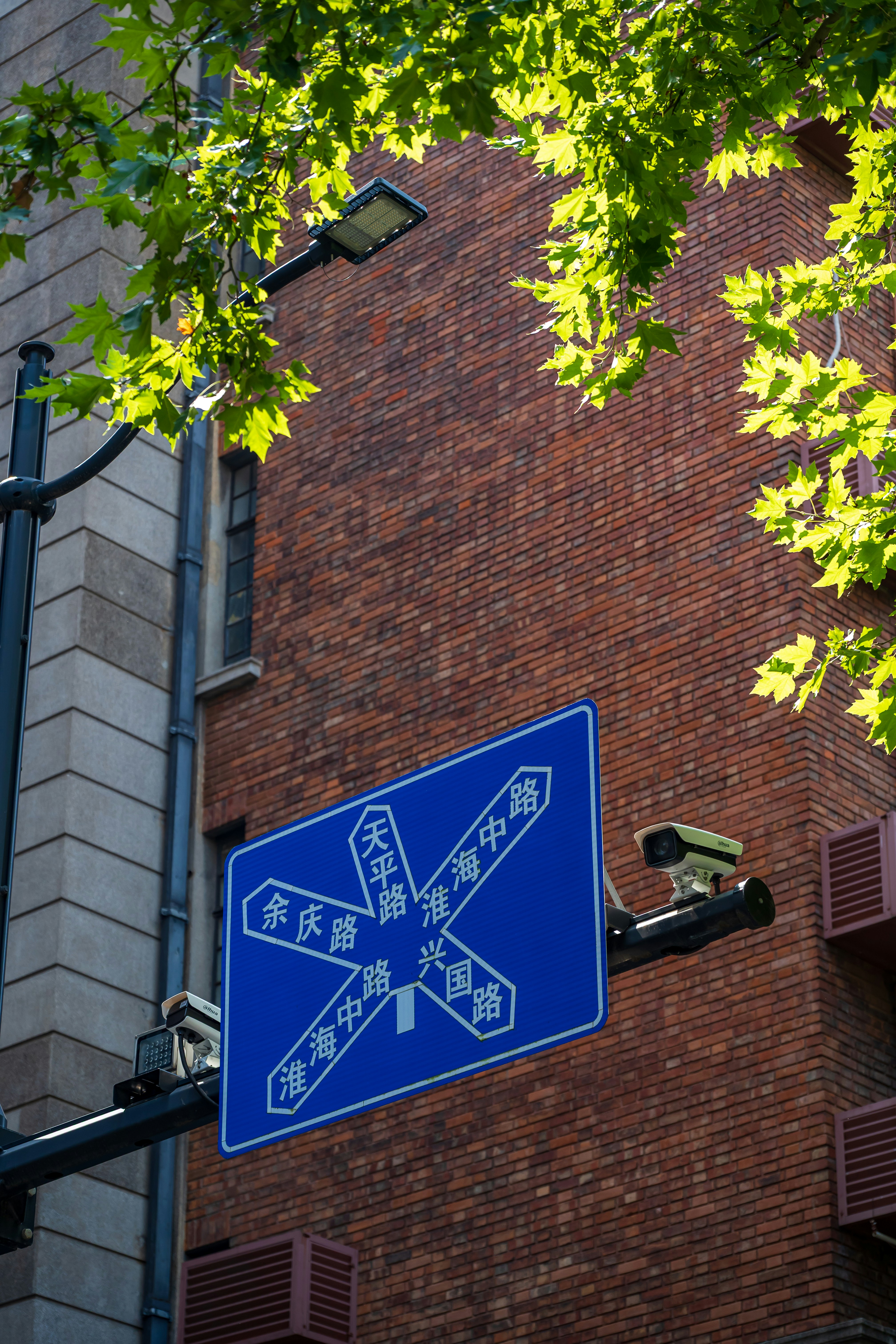 Blue directional sign with chinese characters and cameras.