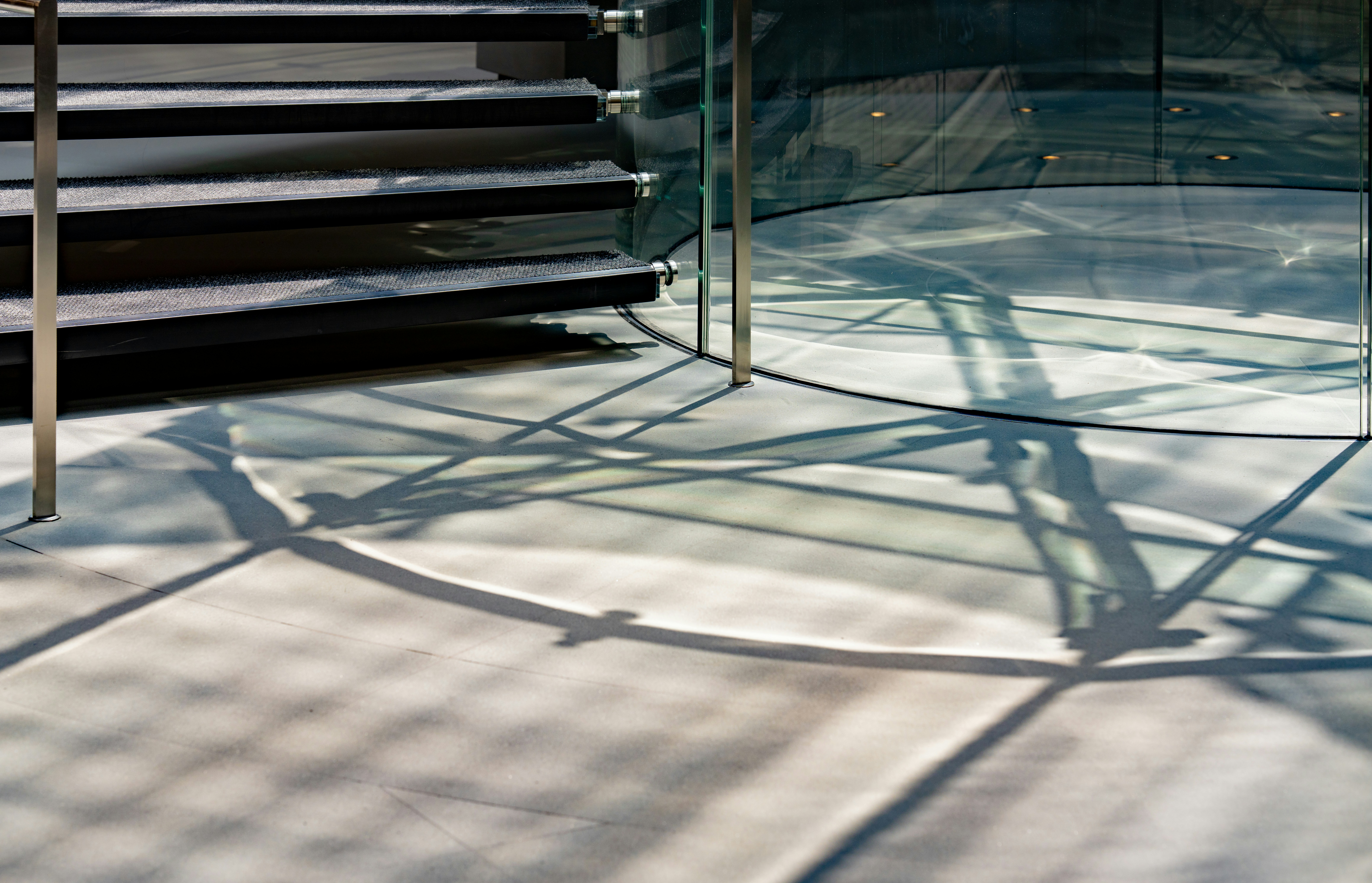 Shadows cast on a glass floor from stairs.