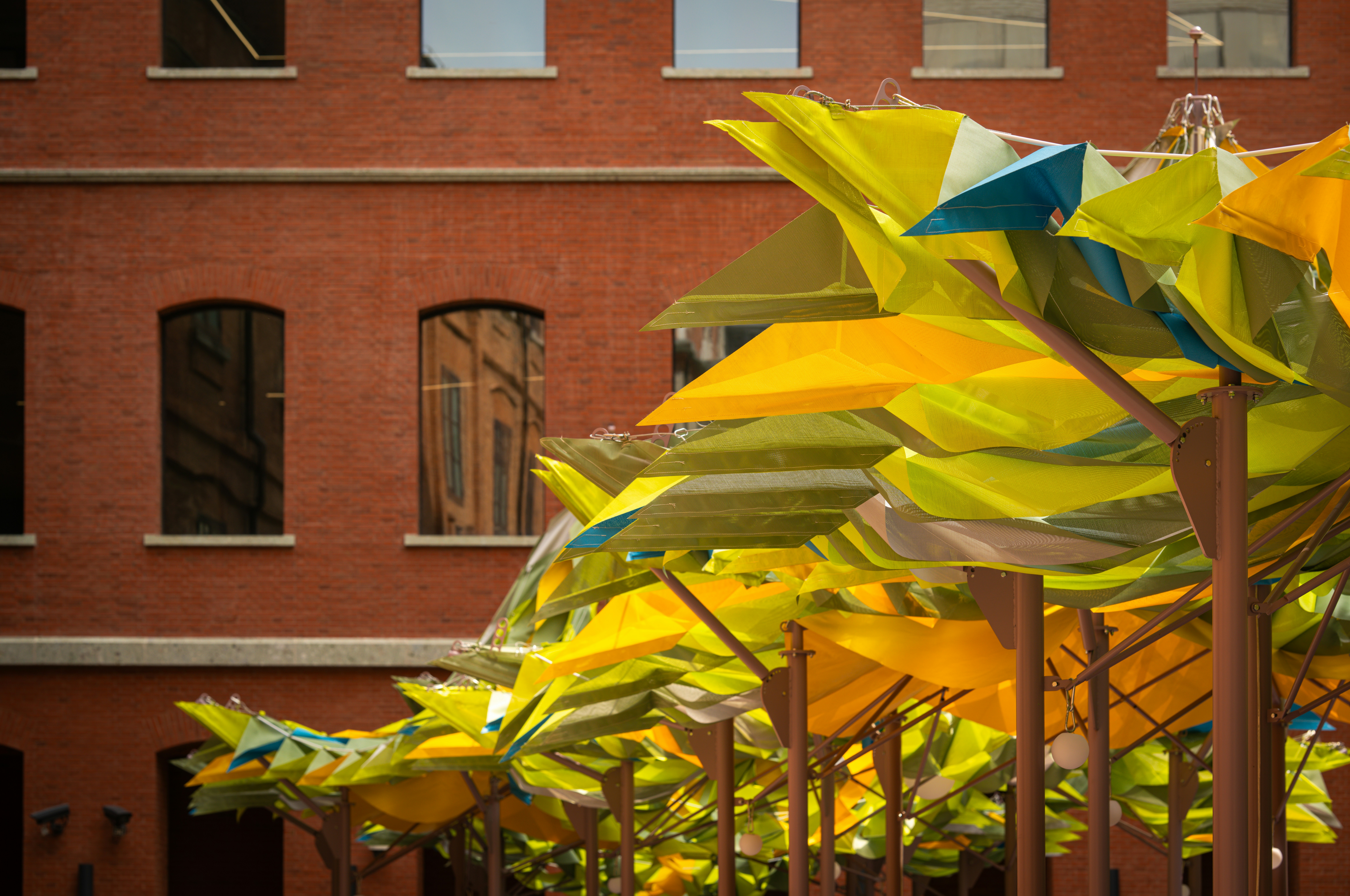 Chromatic Sail Canopies Over a Red Brick Courtyard
