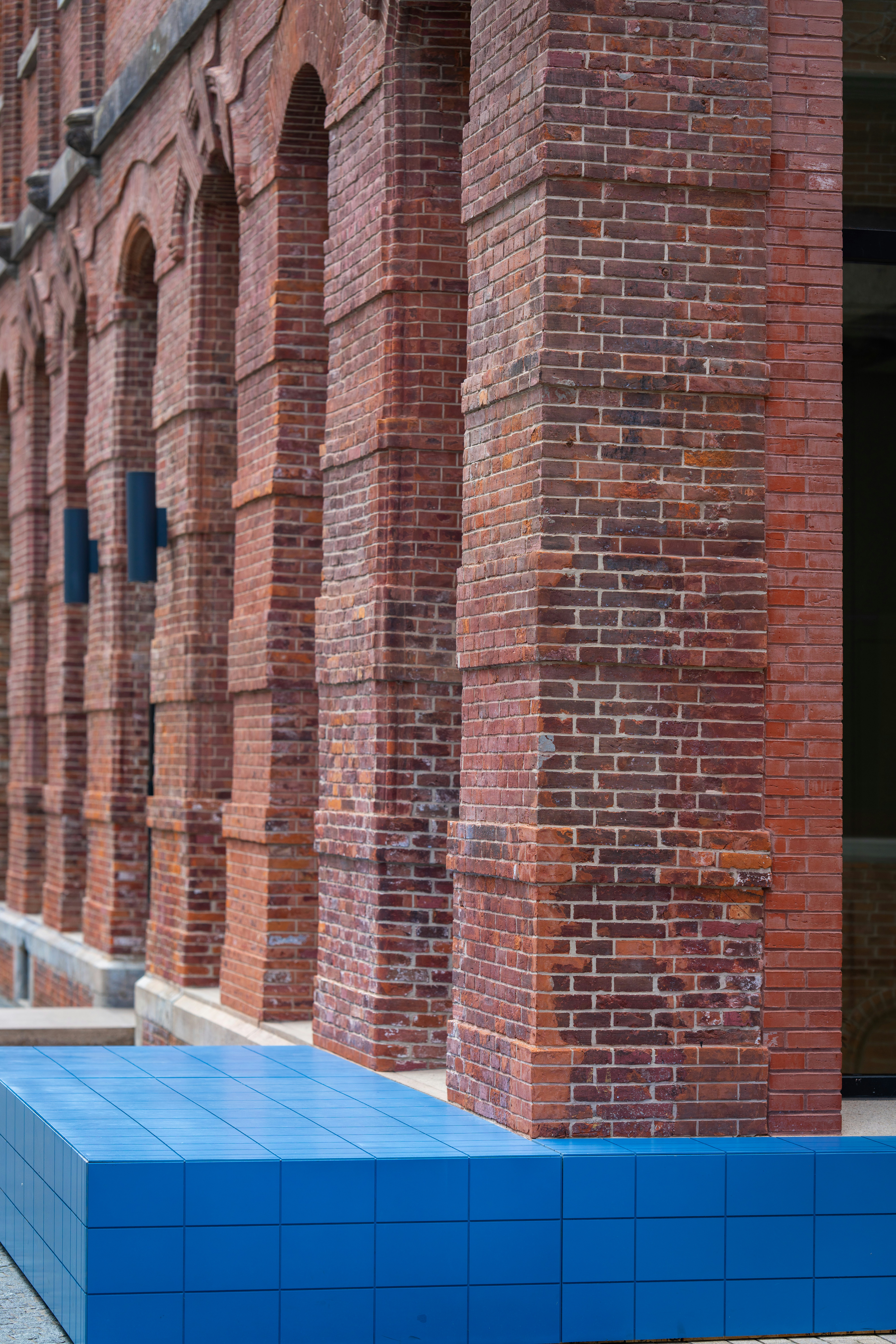 Rhythmic Brick Archway Corridor Framed by a Blue Tile Foreground