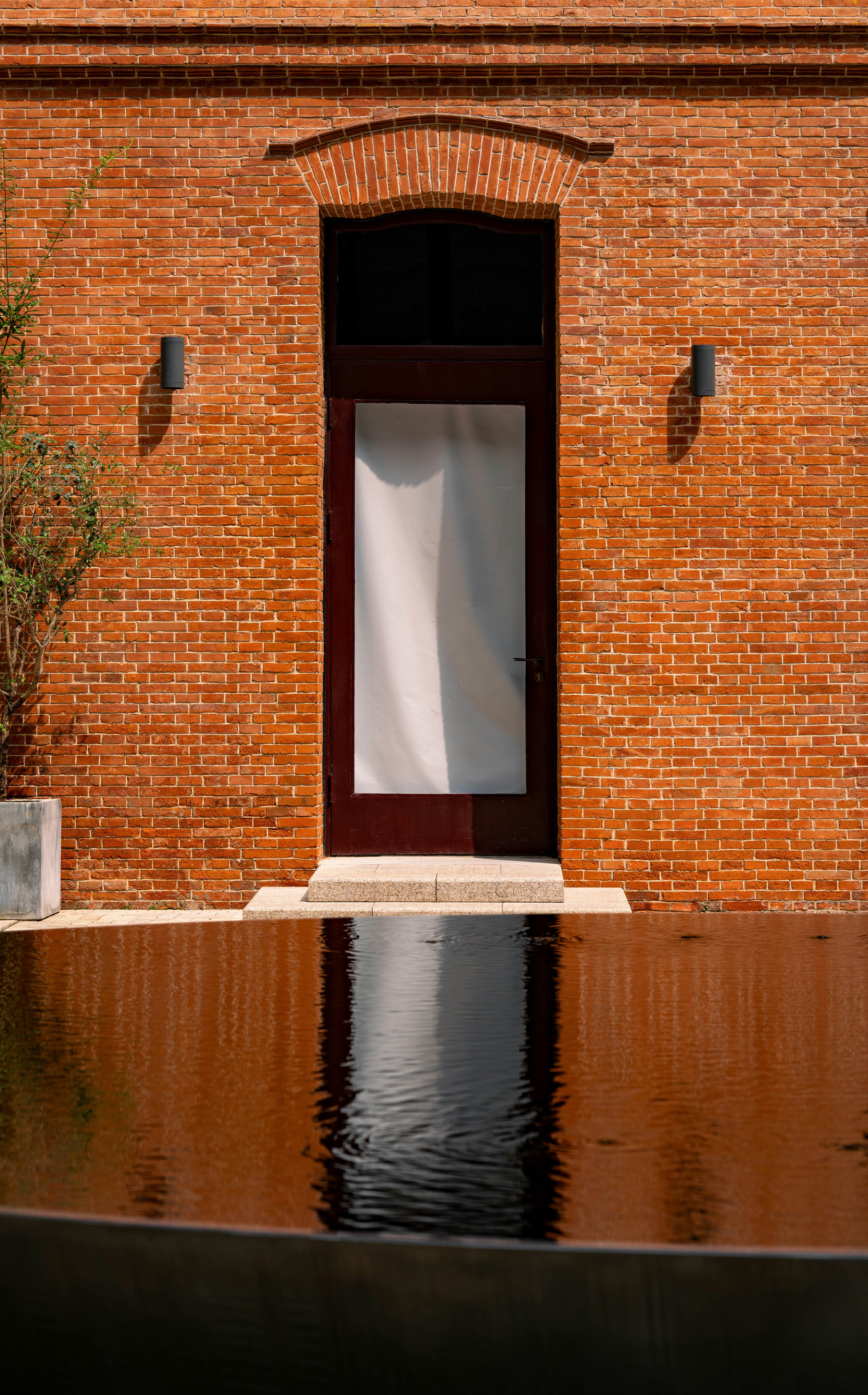 Brick wall with a door reflected in dark water.