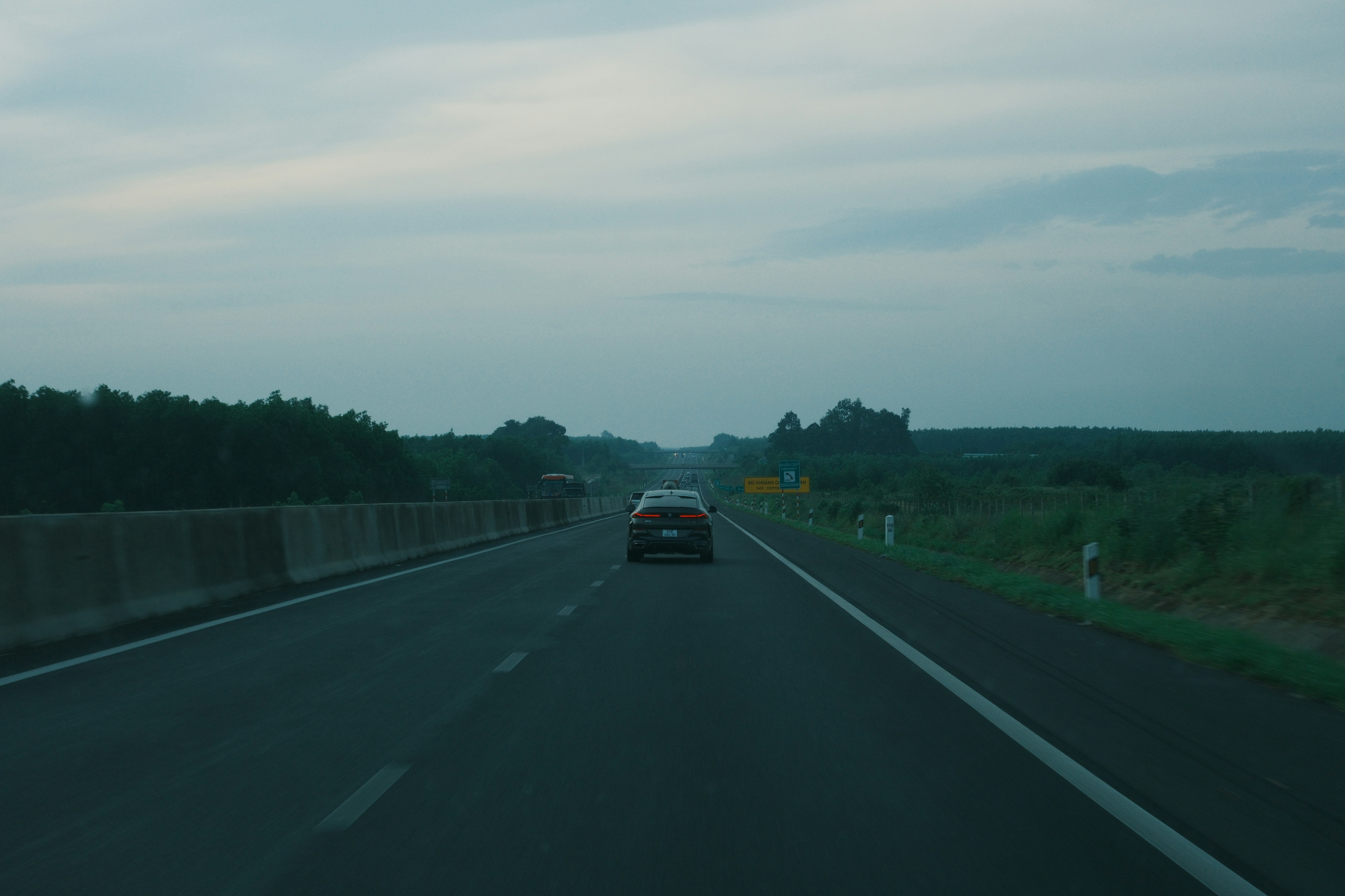 Dusk Highway: A lone car threads toward the horizon