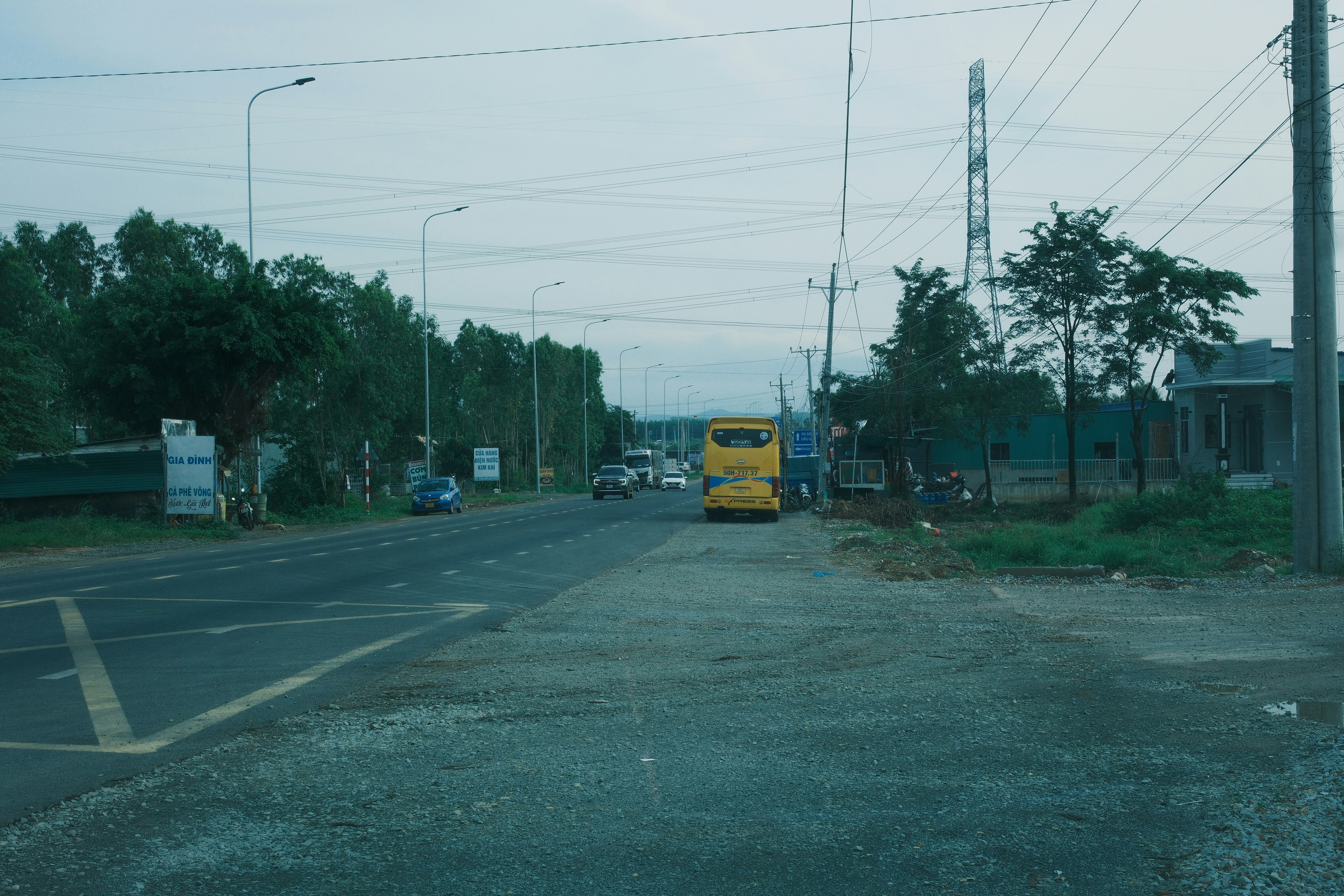 Yellow bus on a road with trees and buildings