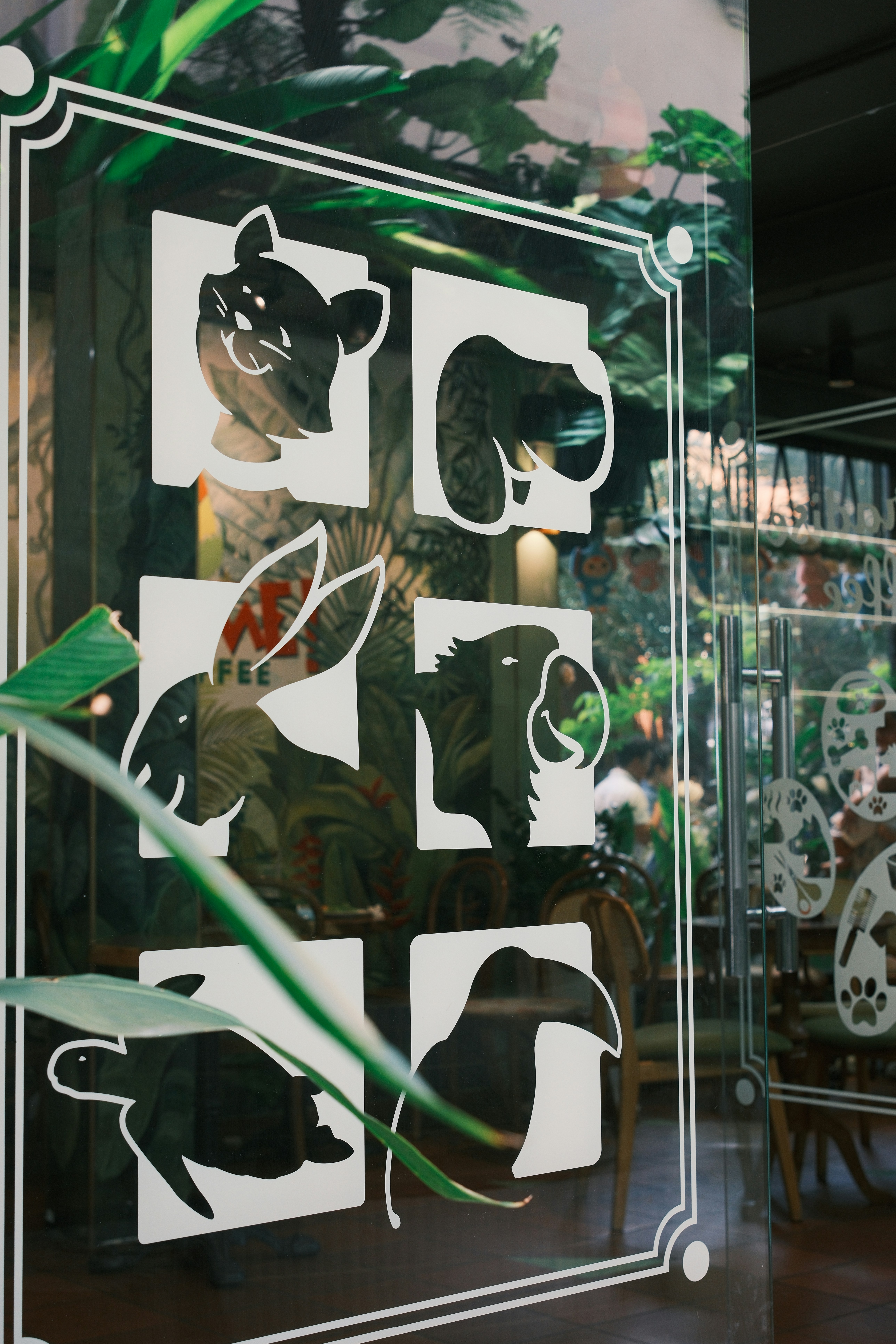 Nine White Silhouettes on Glass: A Café Door Framed by Tropical Reflections