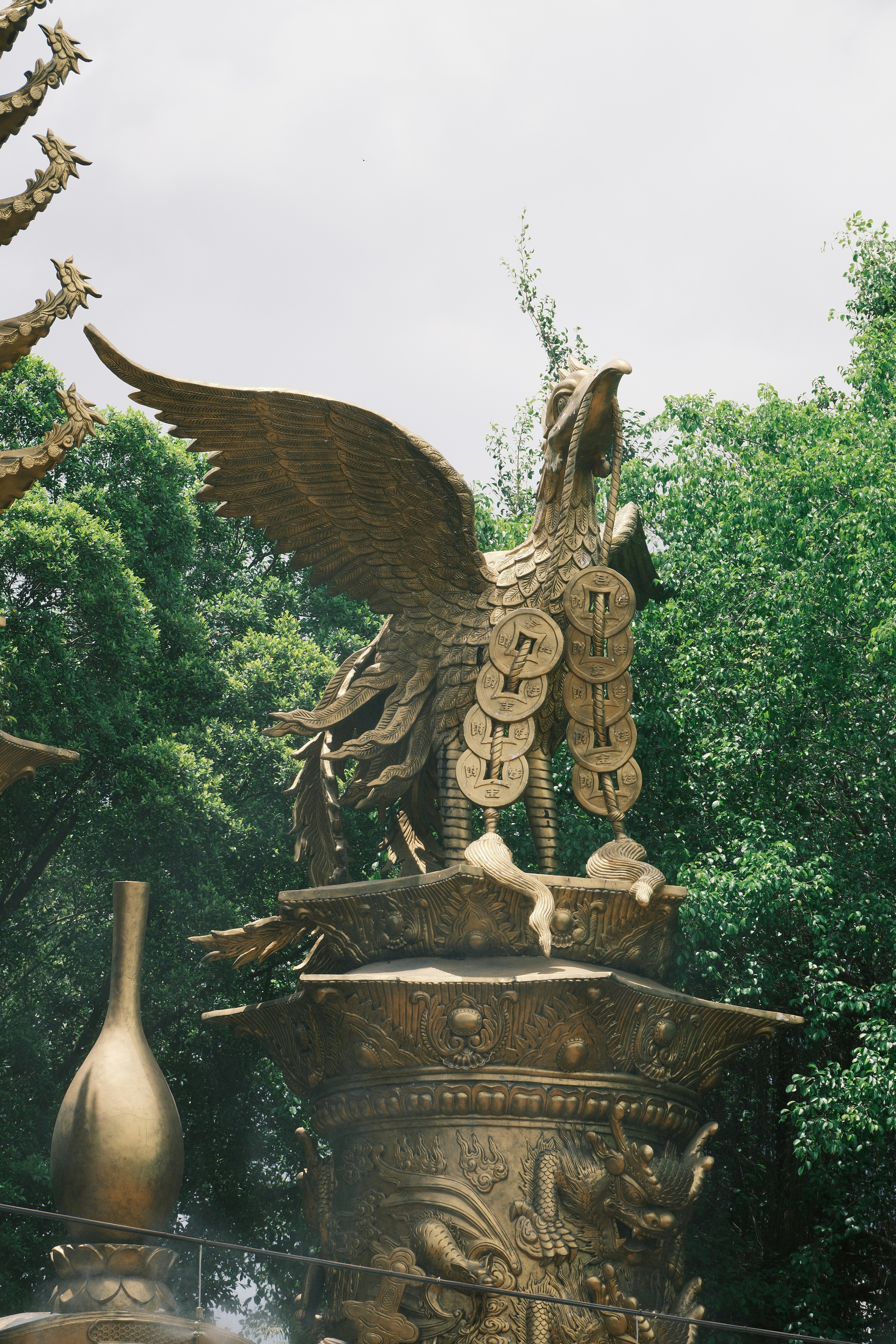 Golden phoenix sculpture adorned with ancient coins.