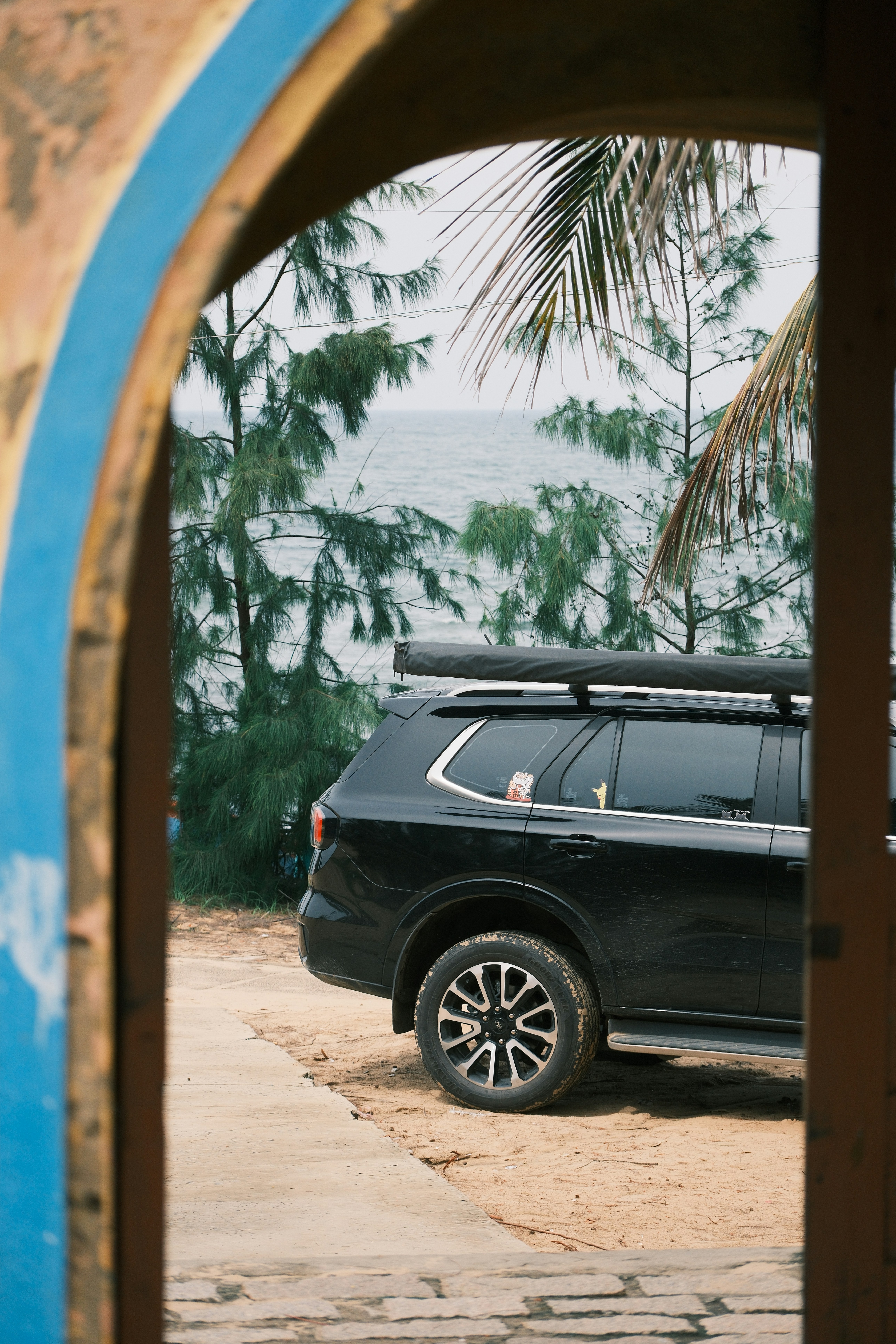 Archway View: A Coastal SUV Framed by Palm and Sea